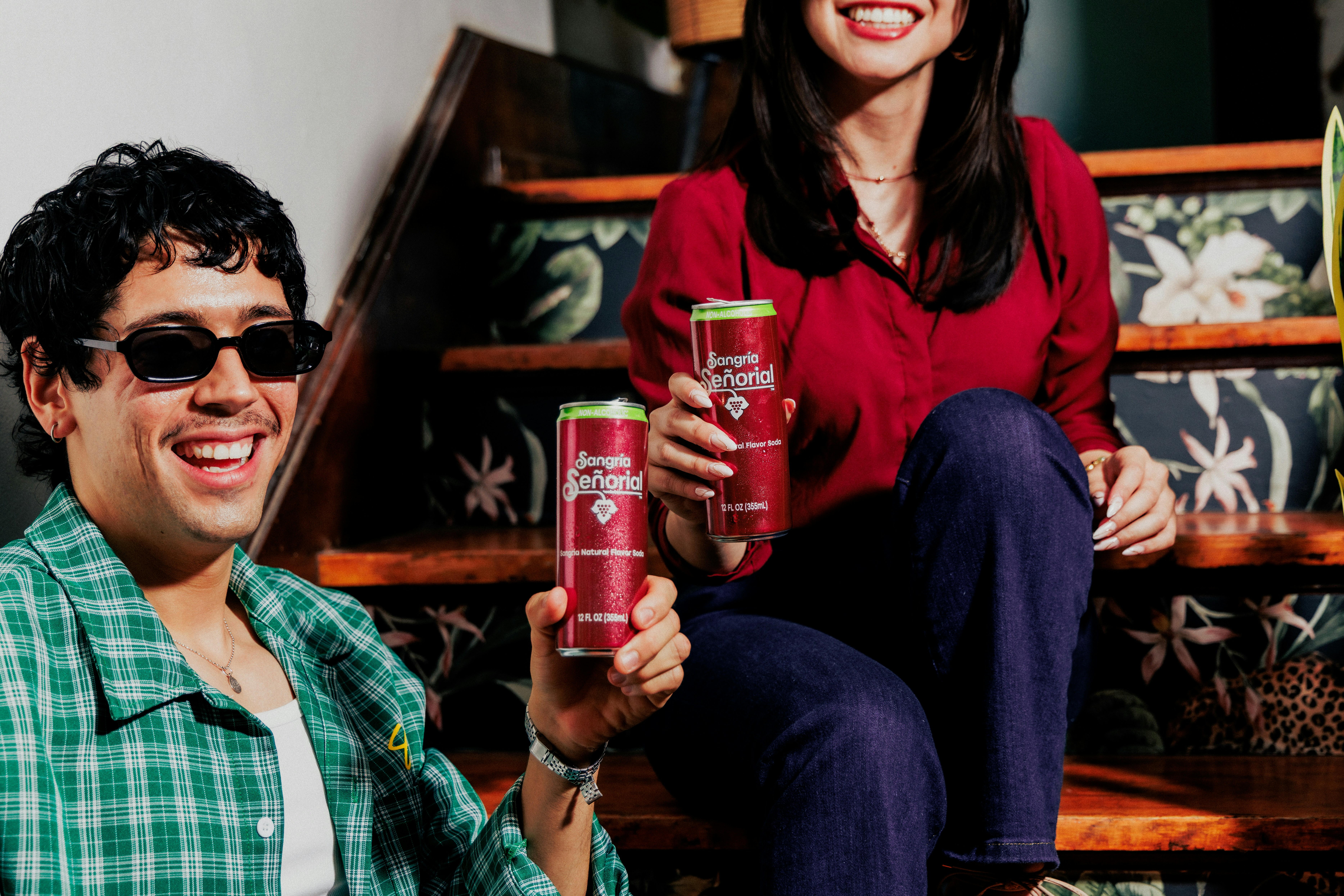 Cheers on the Steps: Two Friends Raise Cans in a Colorful Stairwell