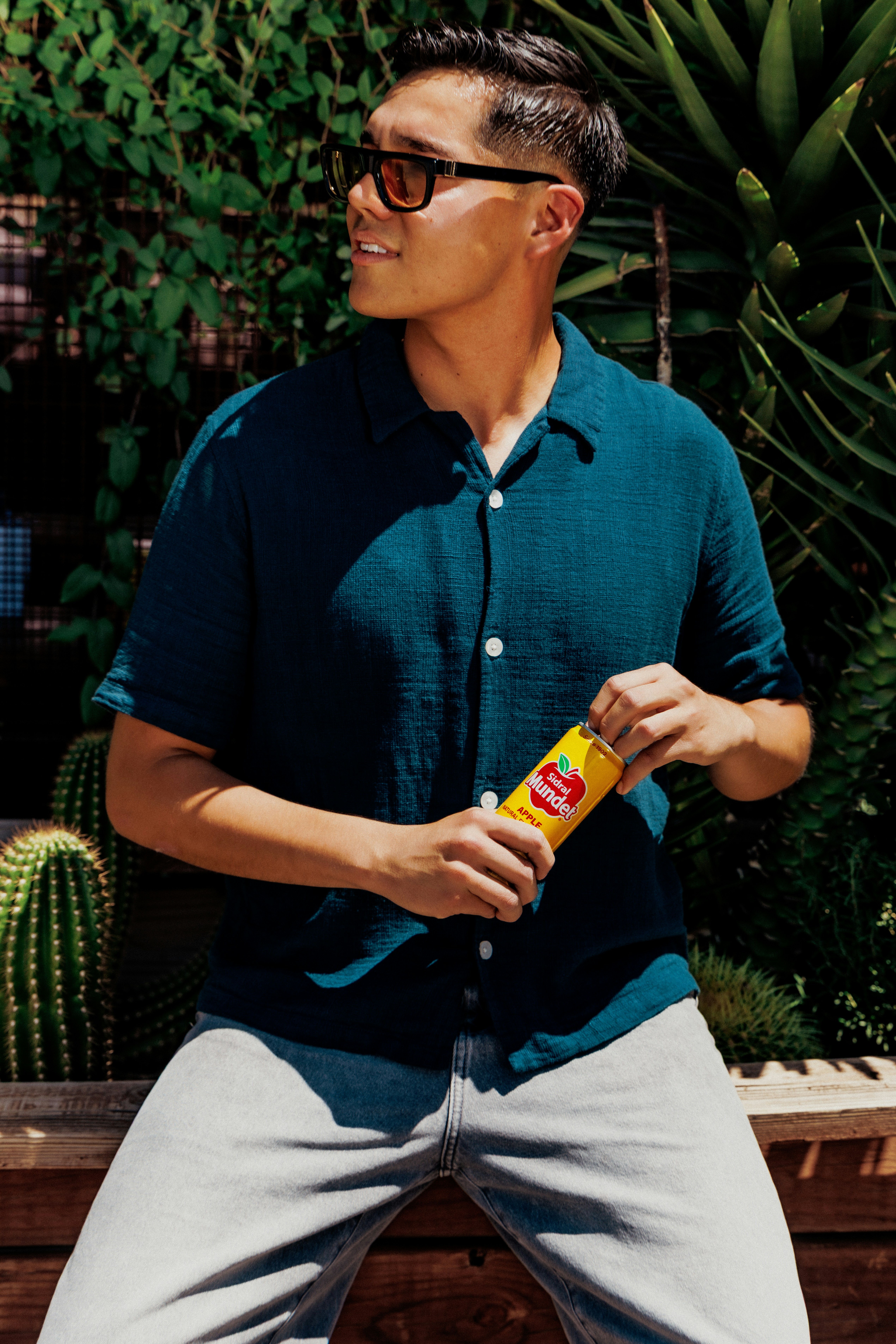 Sunlit Confidence: A man in teal polo enjoying a sunny moment with a beverage