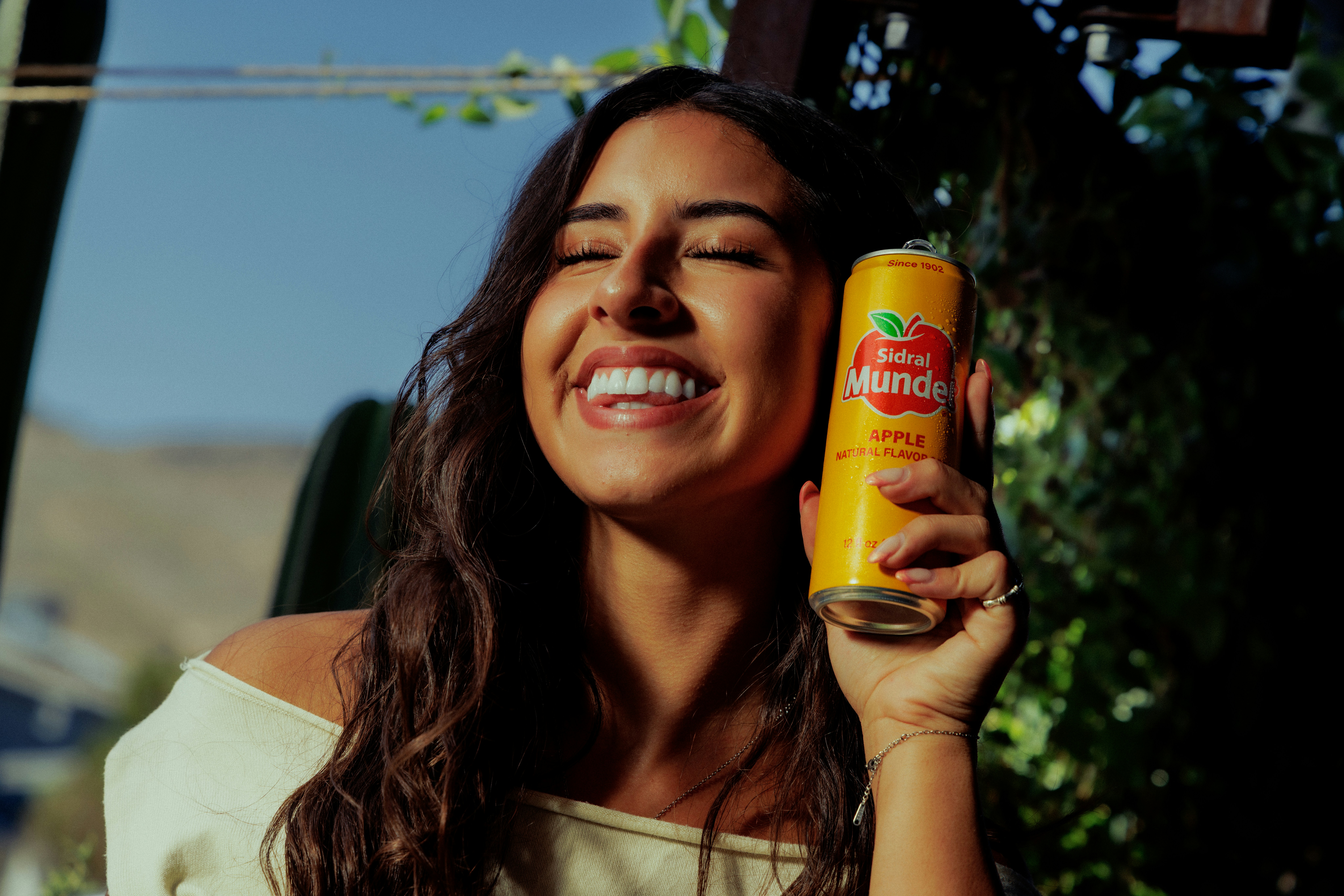 Sunlit Smile: A Woman Enjoys a Moment with a Soda outdoors