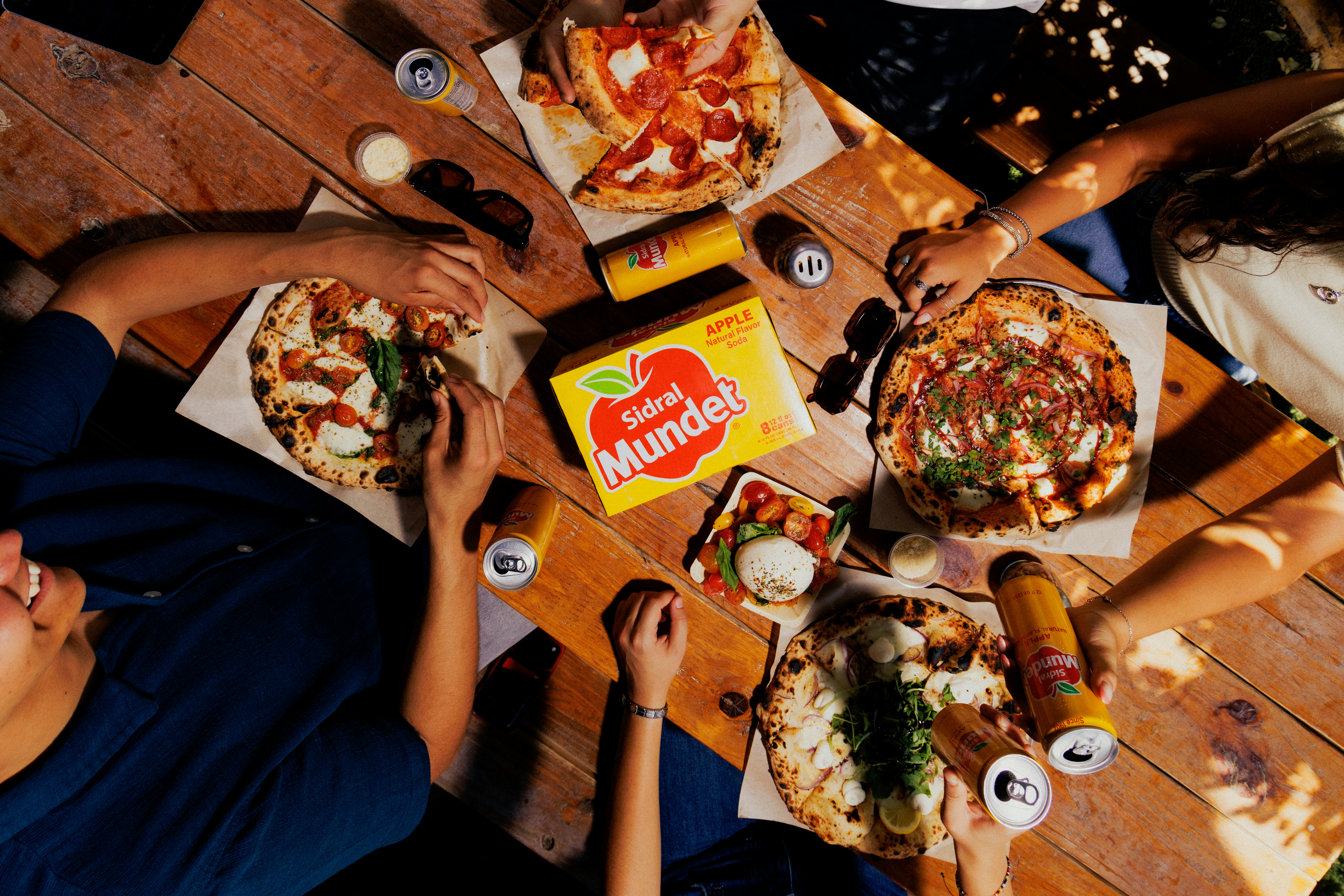 Shared Slice: Overhead View of Friends Gathering Around Pizzas