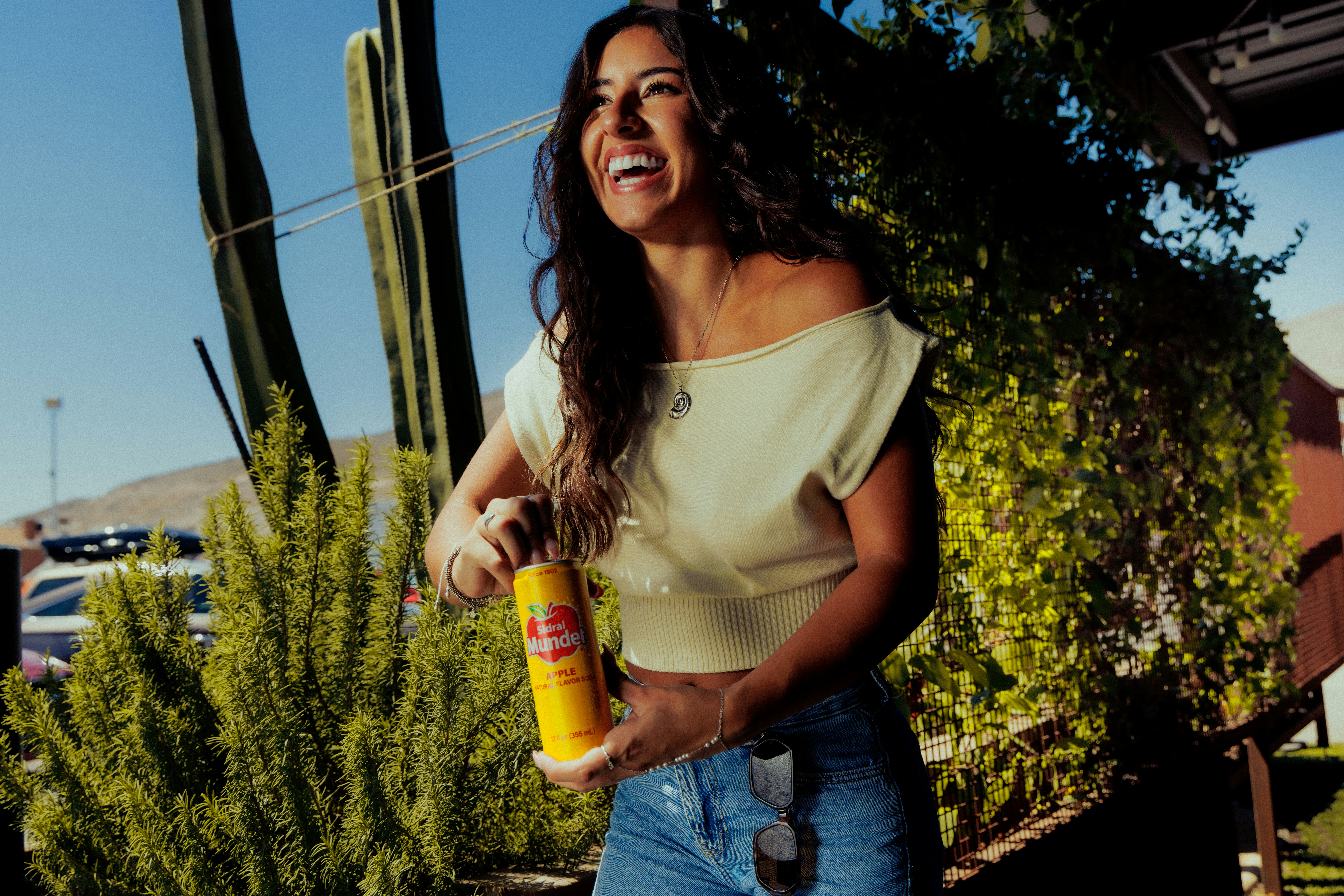Sunny Elation: Woman Laughing with Sunscreen Bottle in a Desert Garden