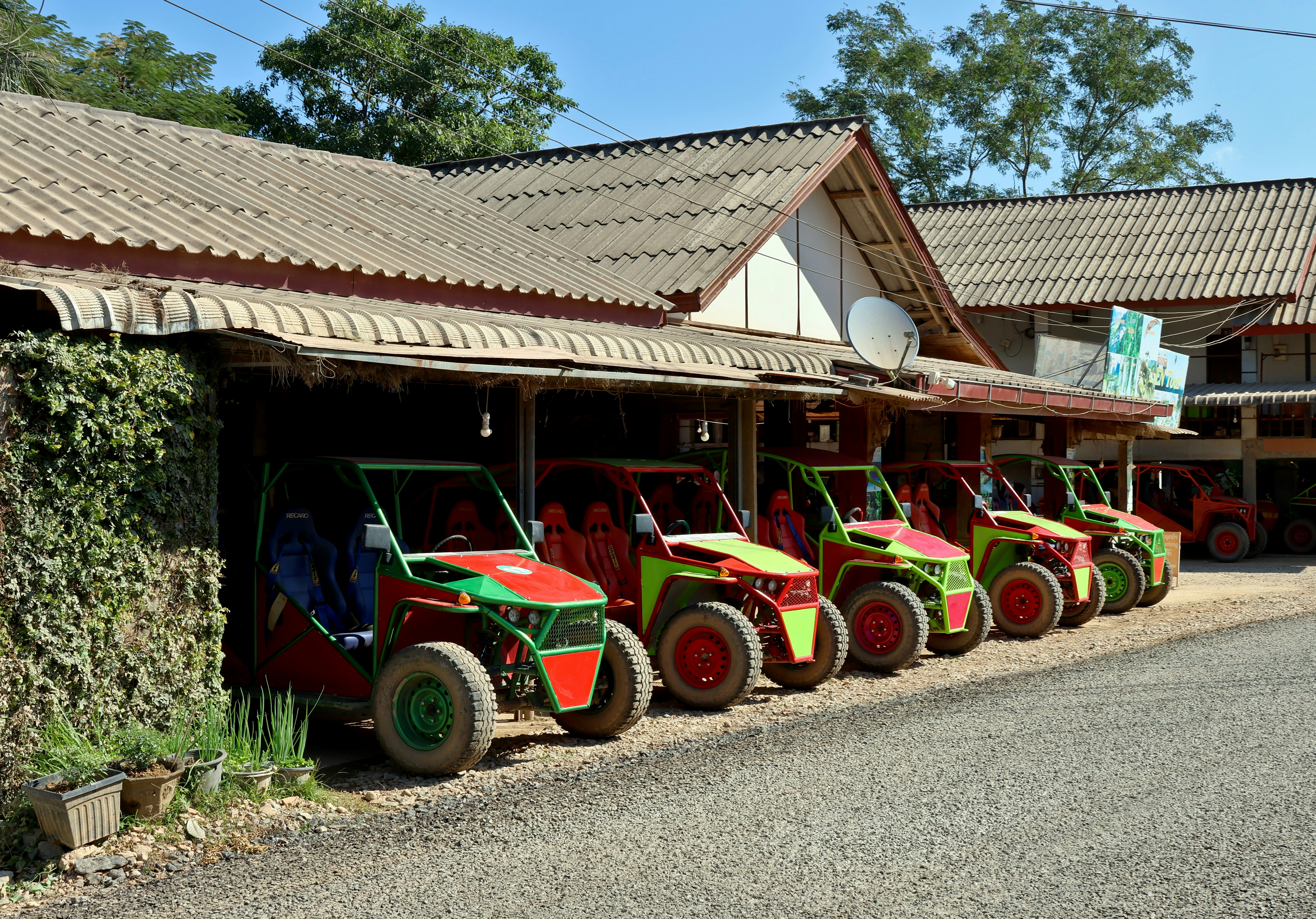 Row of colorful off-roaders lined up beside a rustic workshop