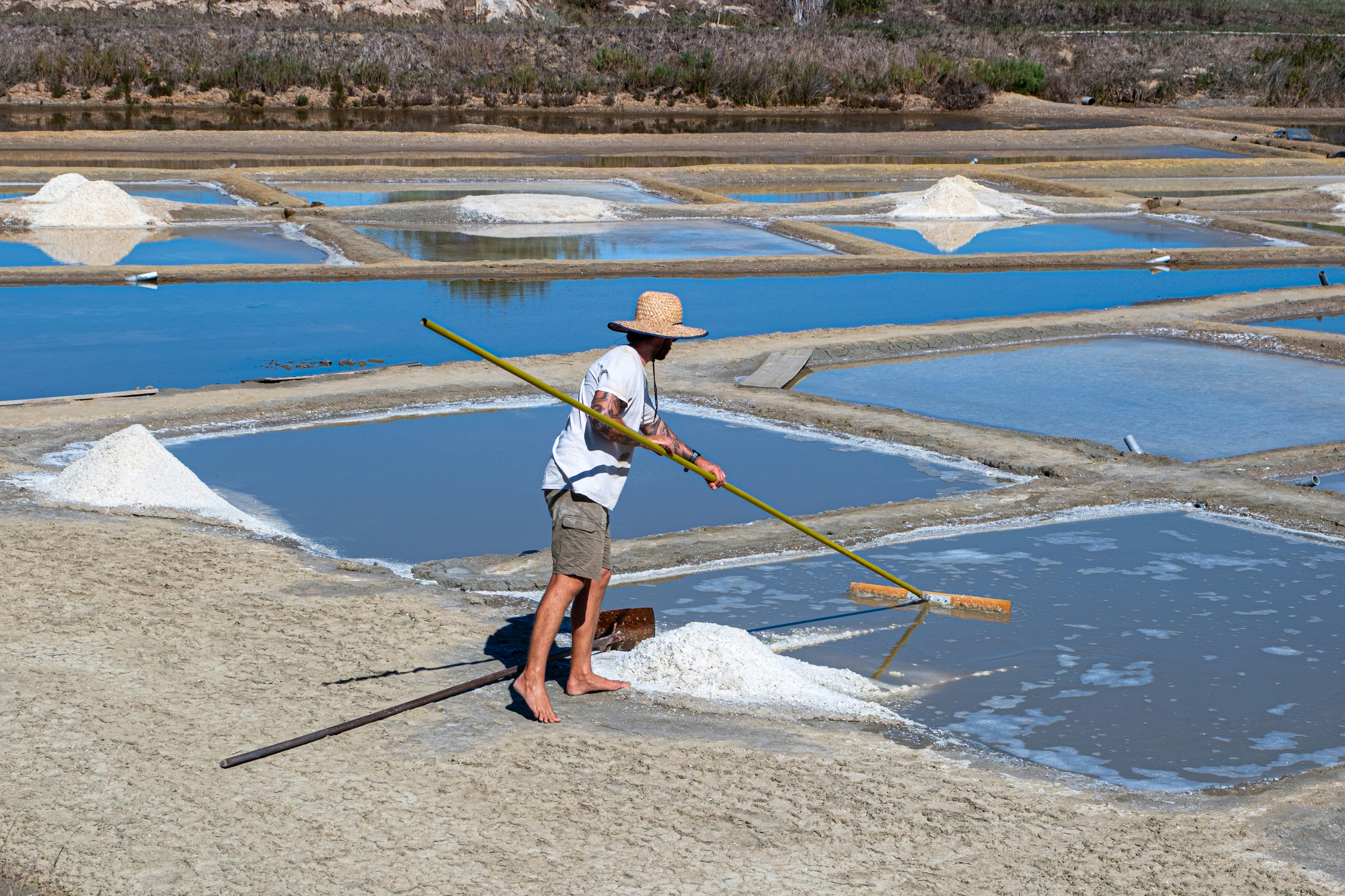 Salt Worker with Long Paddle in a Blue Lagoon Salt Flats