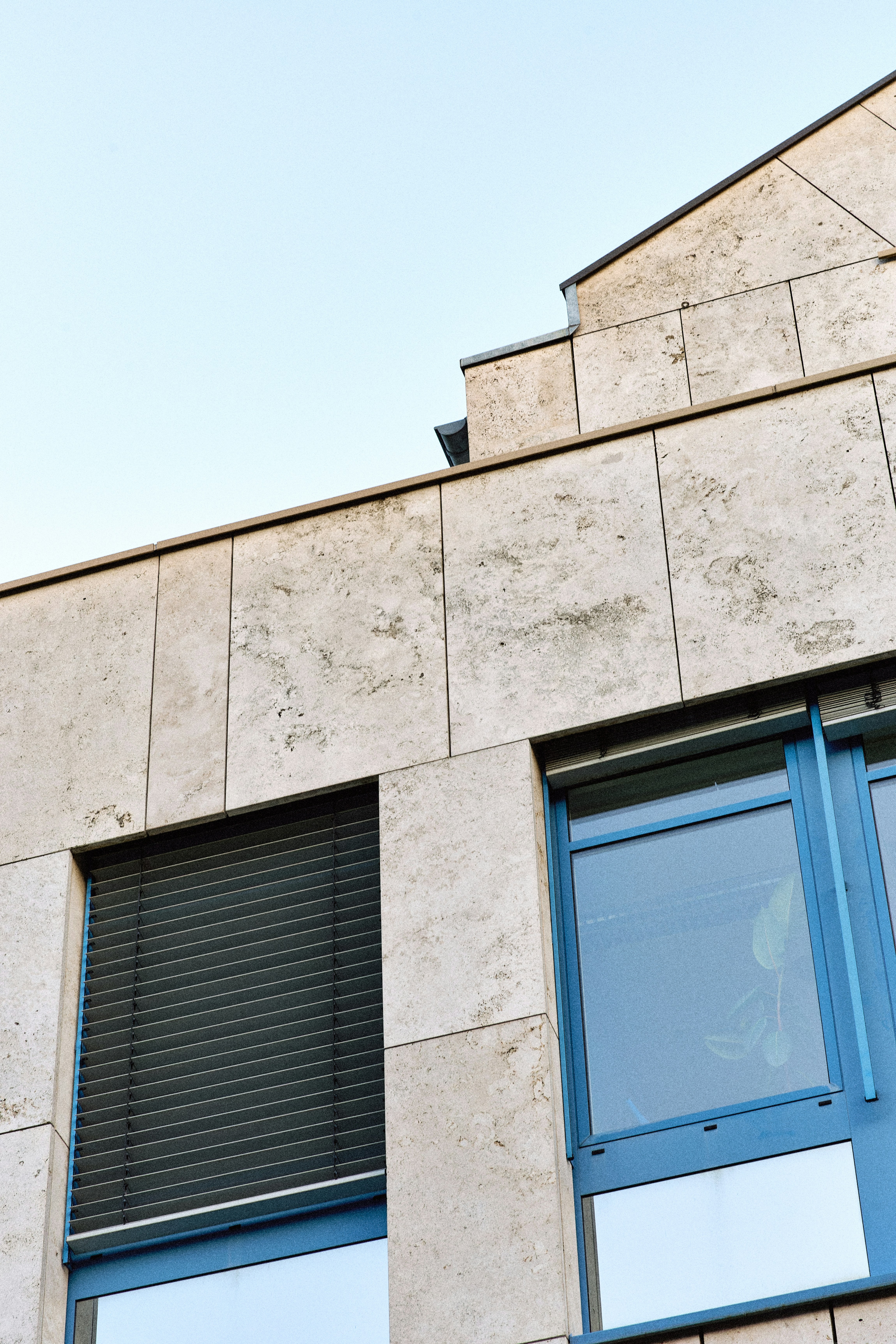 Blue-framed windows against sun-washed stone facade