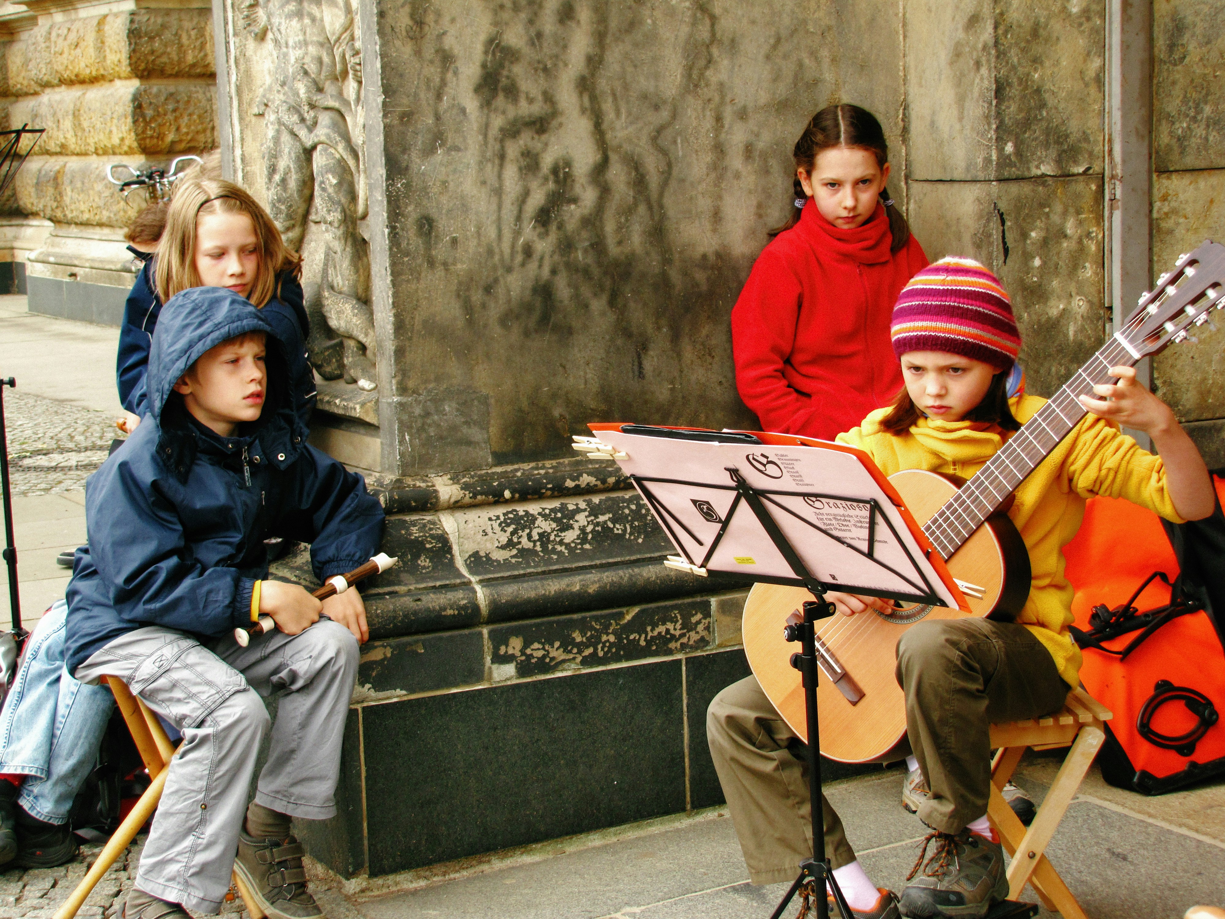 Guitarist in Warm Red and Yellow: Street Ensemble Under Stone Architecture