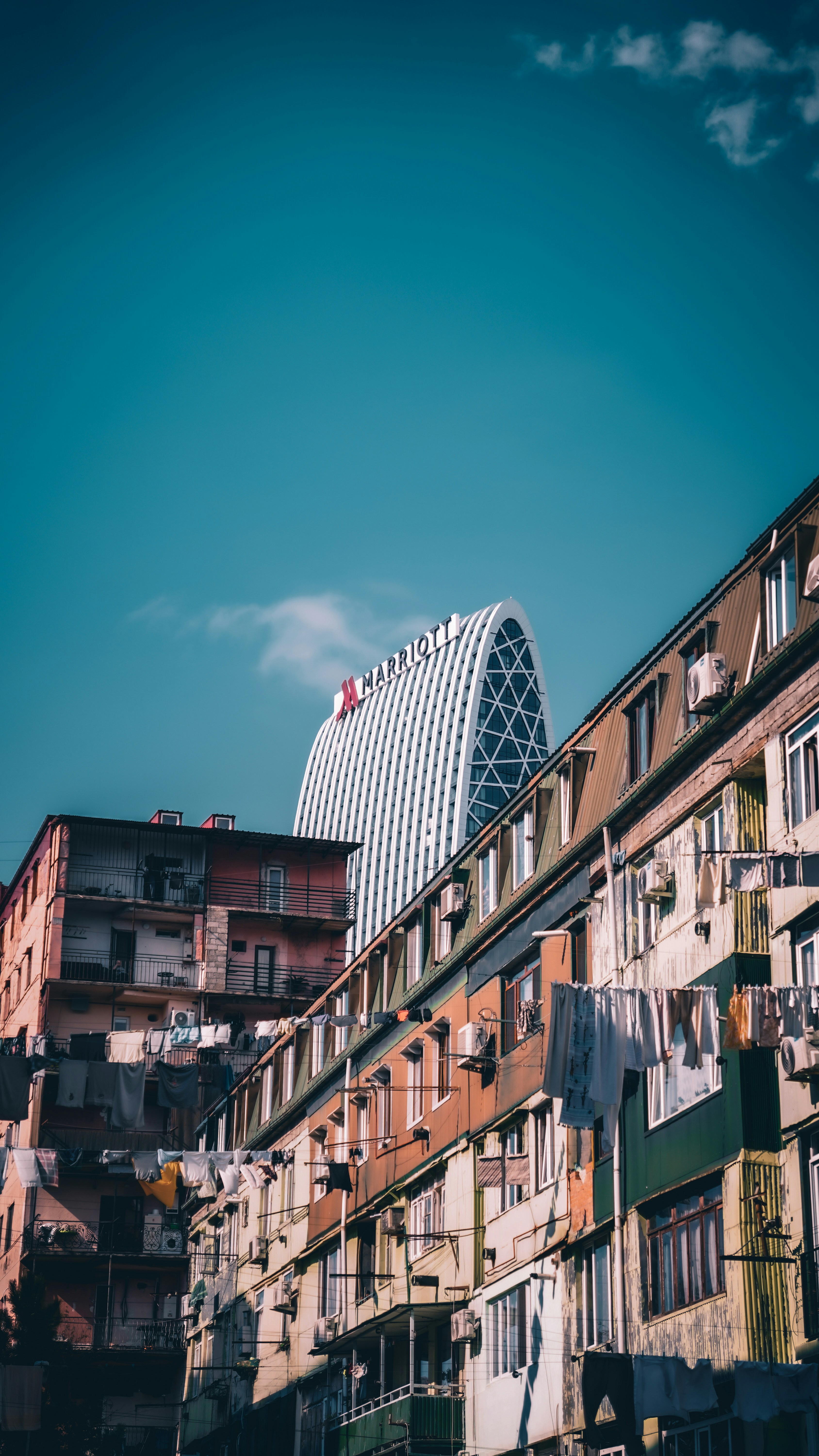 Laundry hanging on lines between old apartment buildings with a modern Marriott hotel behind