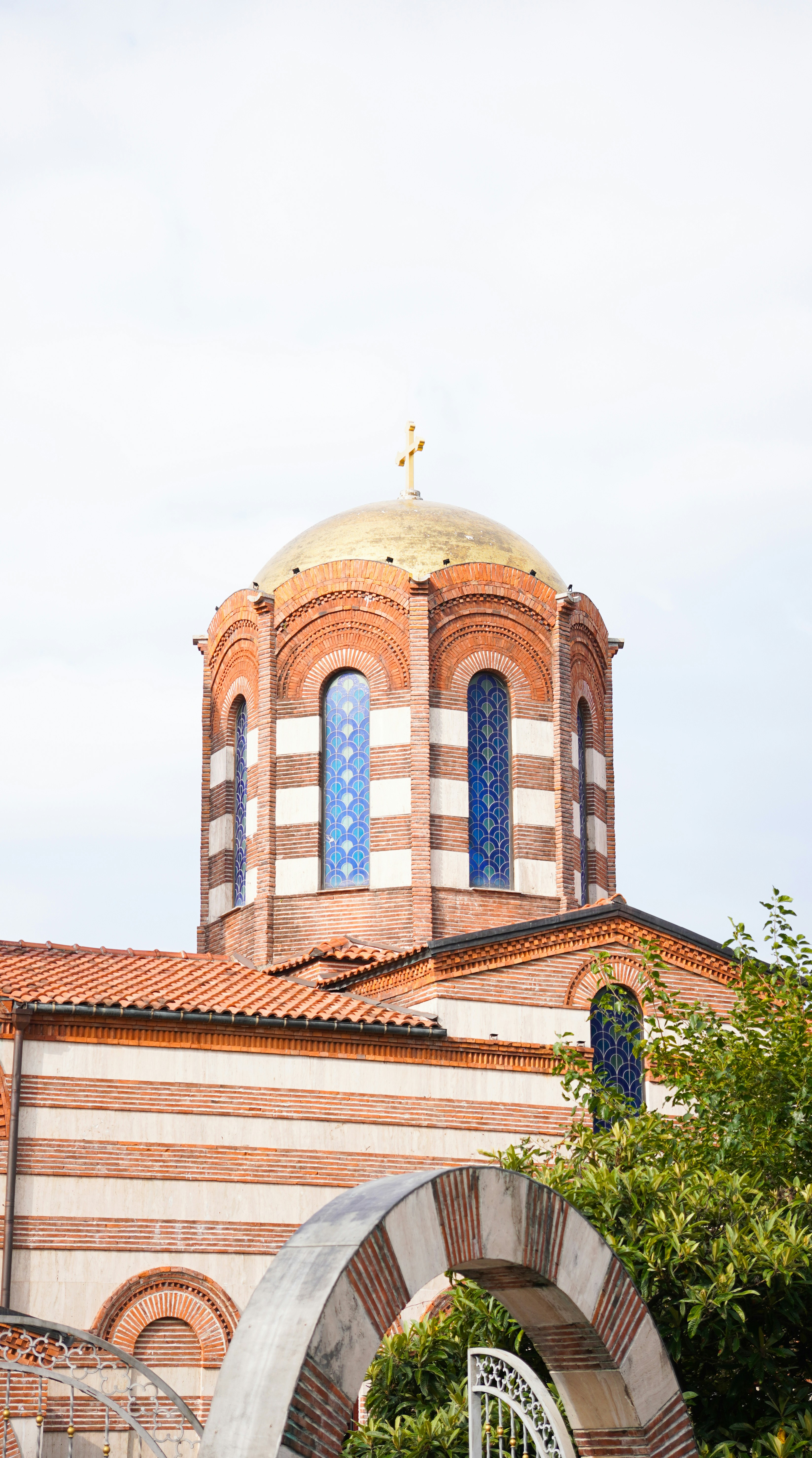 A church dome with red brick and white stone stripes topped by a cross