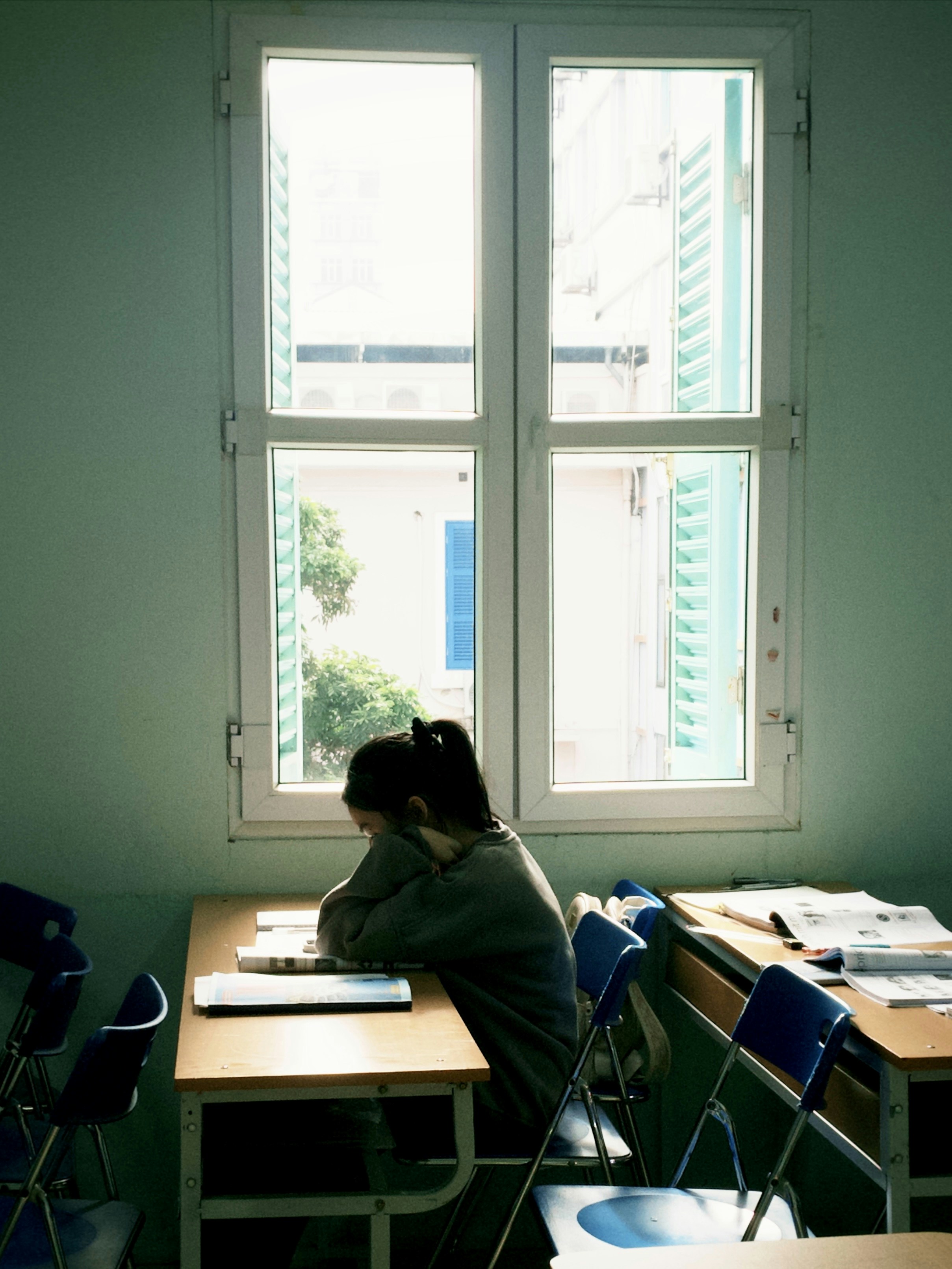Quiet study in a sunlit classroom: a student rests by the window