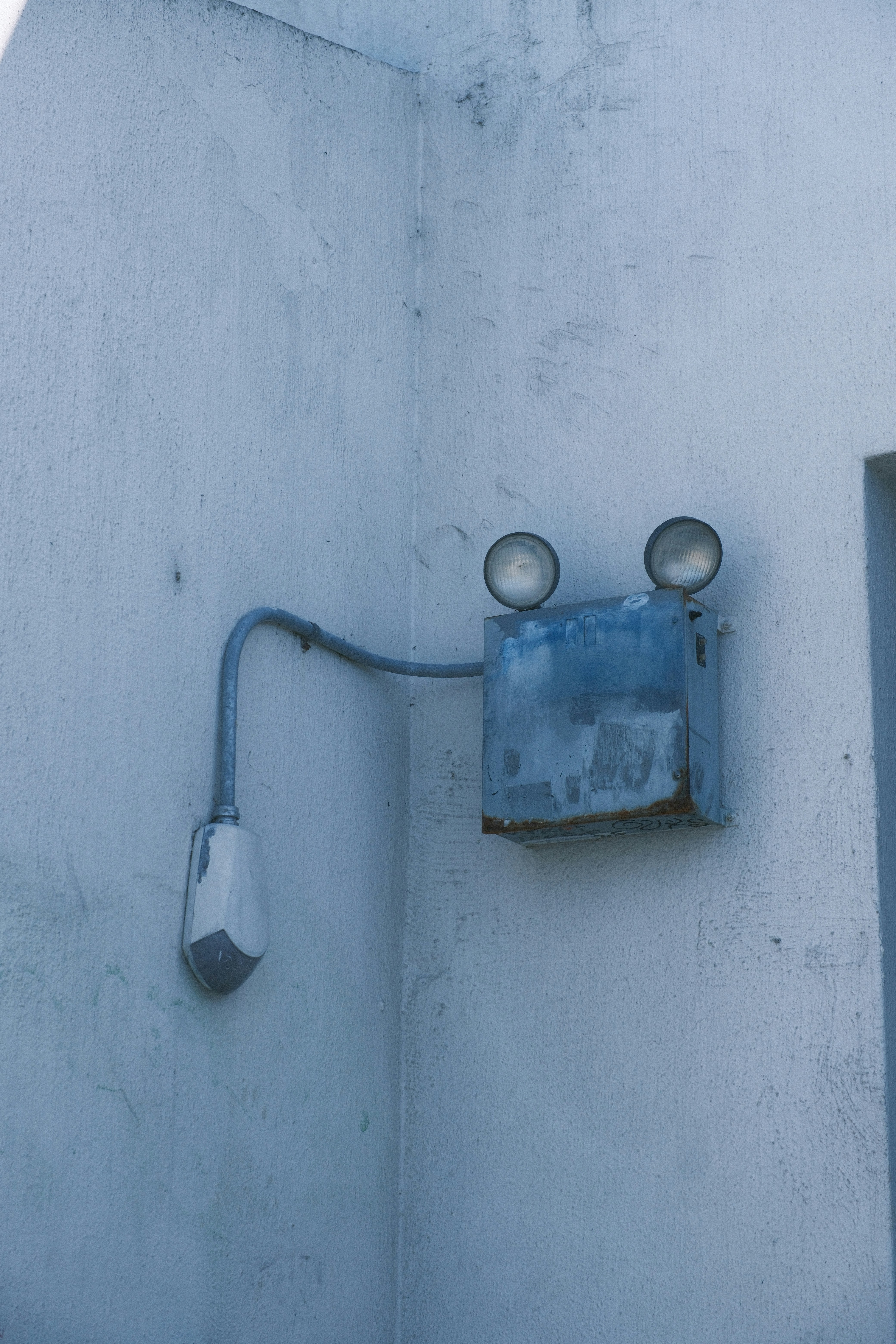 Blue Ventured Wall: A Weathered Corner with Concrete Box and Dual Lamps