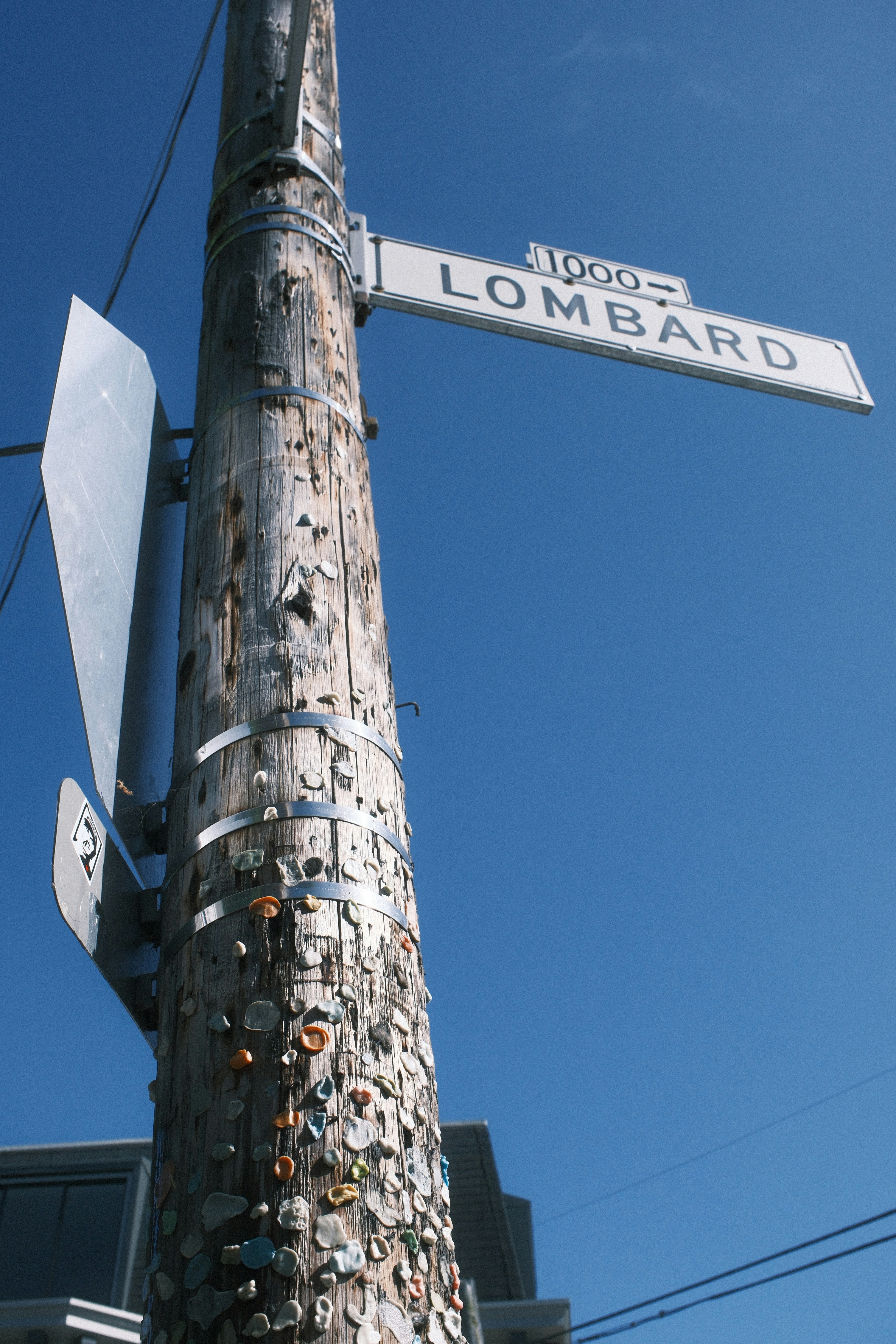 Weathered street pole crowned with a sign: Lom bard