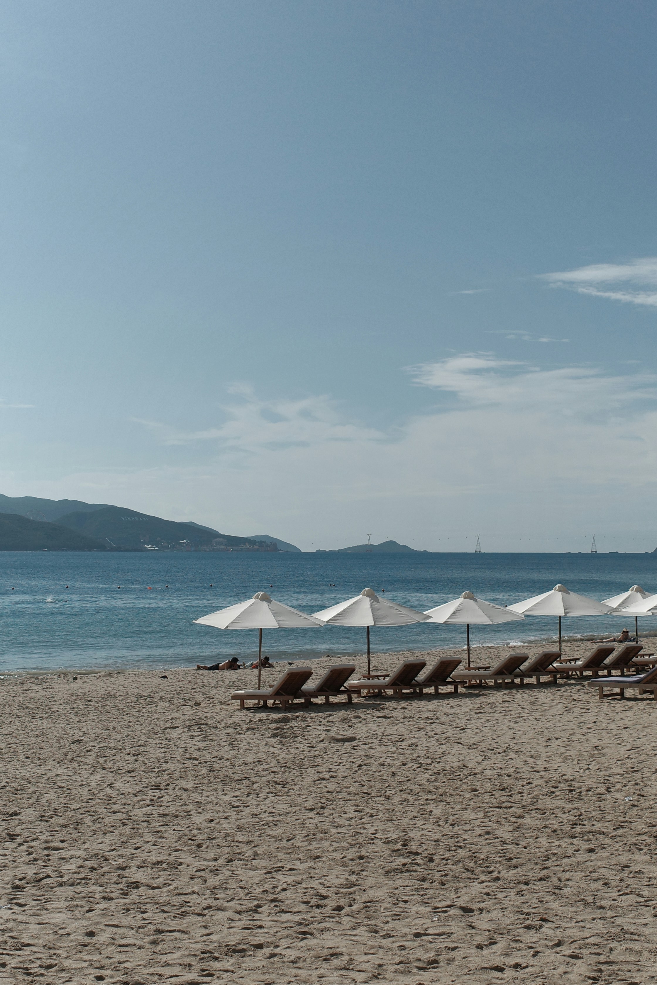 Line of Beach Chairs Under White Umbrellas Guarding the Calm Sea