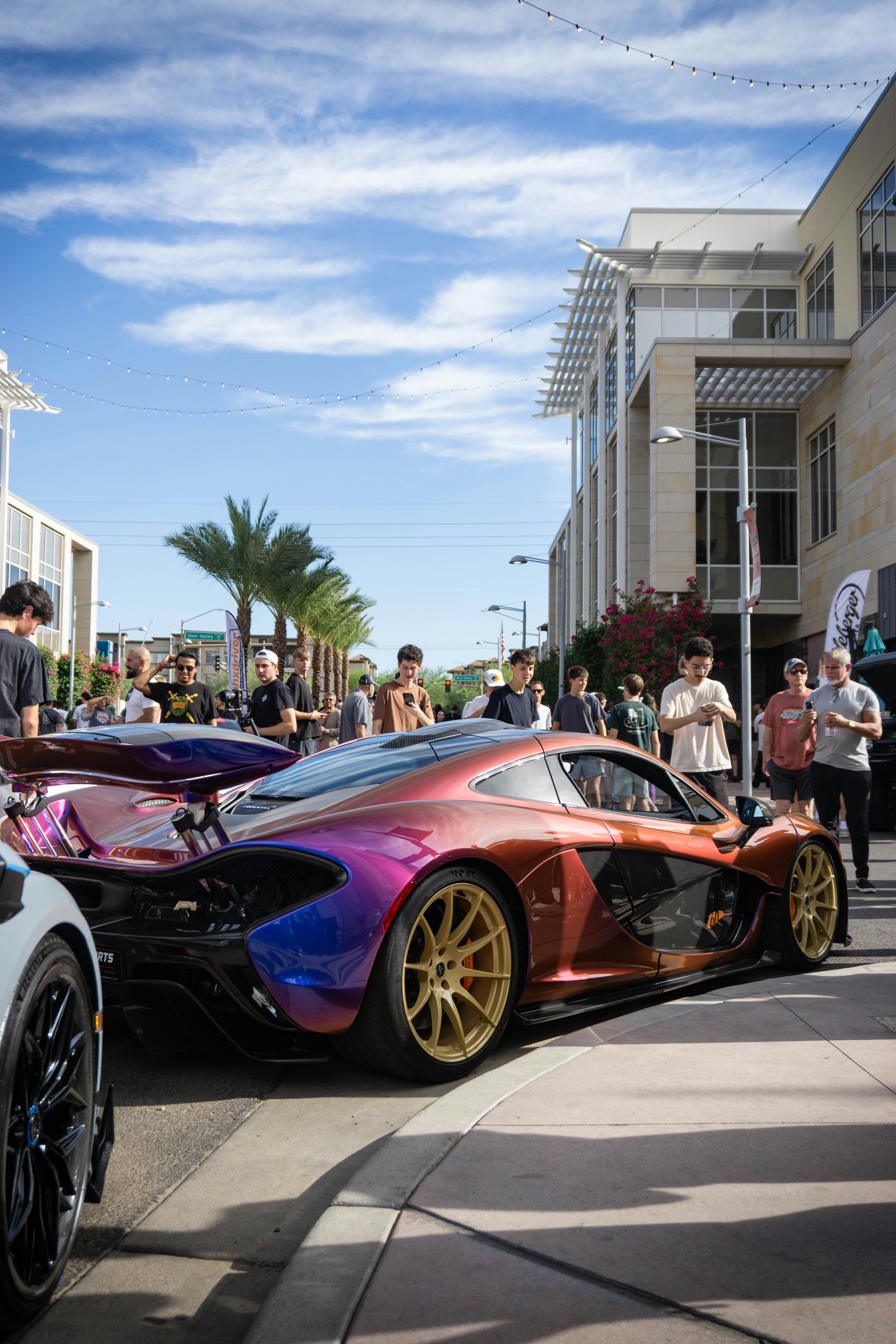 Vibrant Koenigsegg at a sunlit car show along a modern plaza