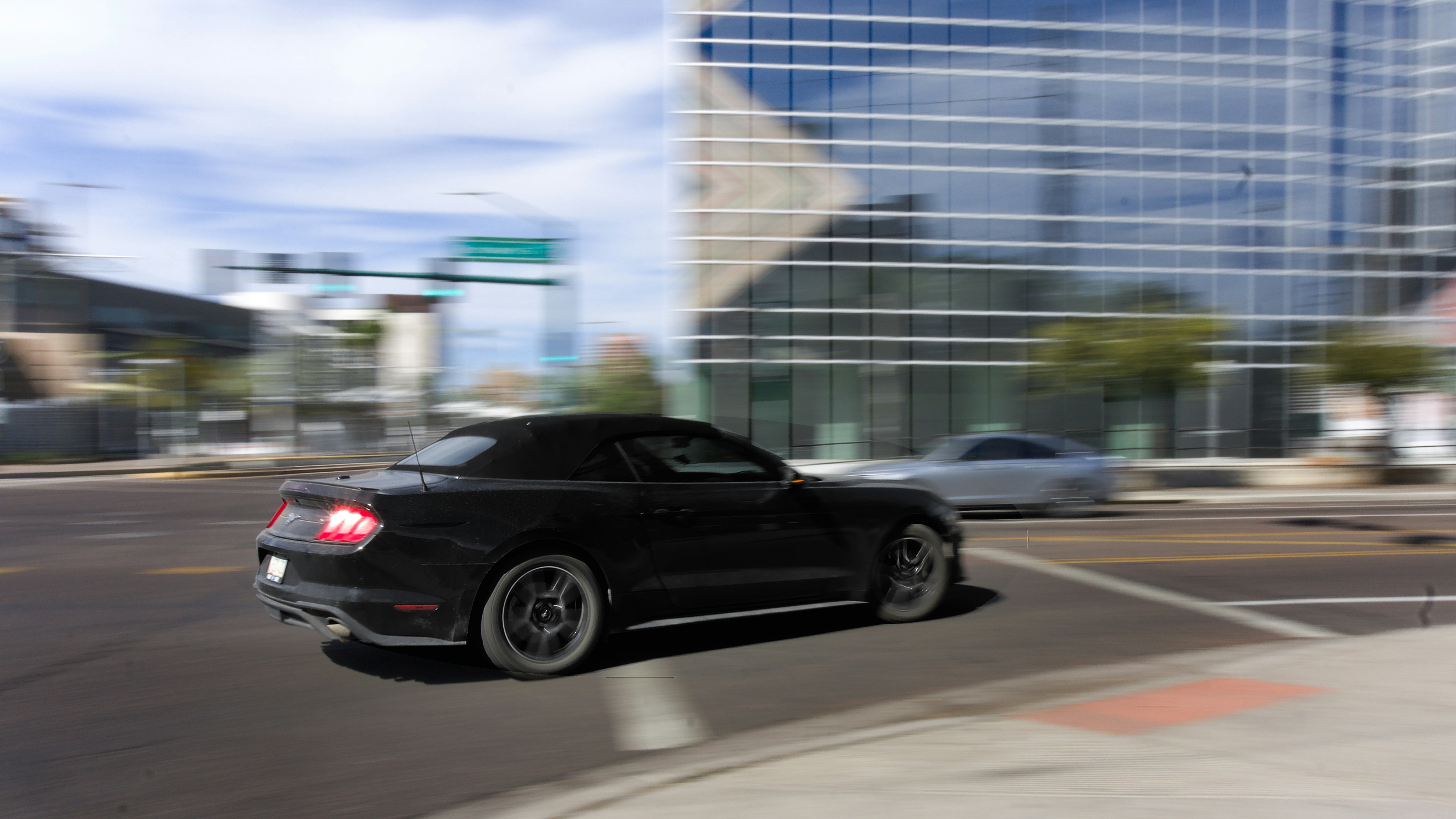 Black Mustang in Motion Through Downtown Glass and Steel
