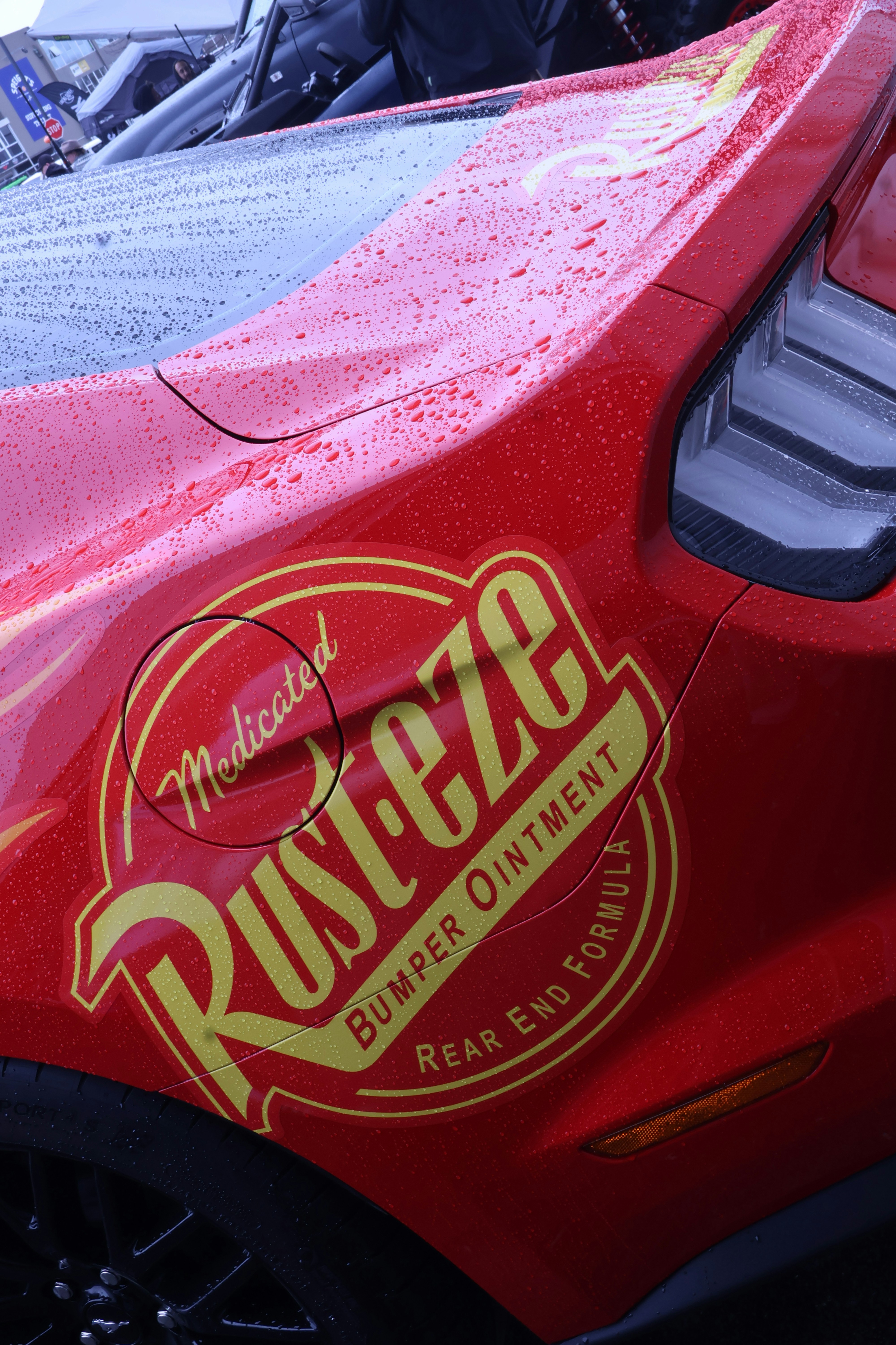 Red Race Car Emblem: Medical Formula on a Rain-Dotted Body