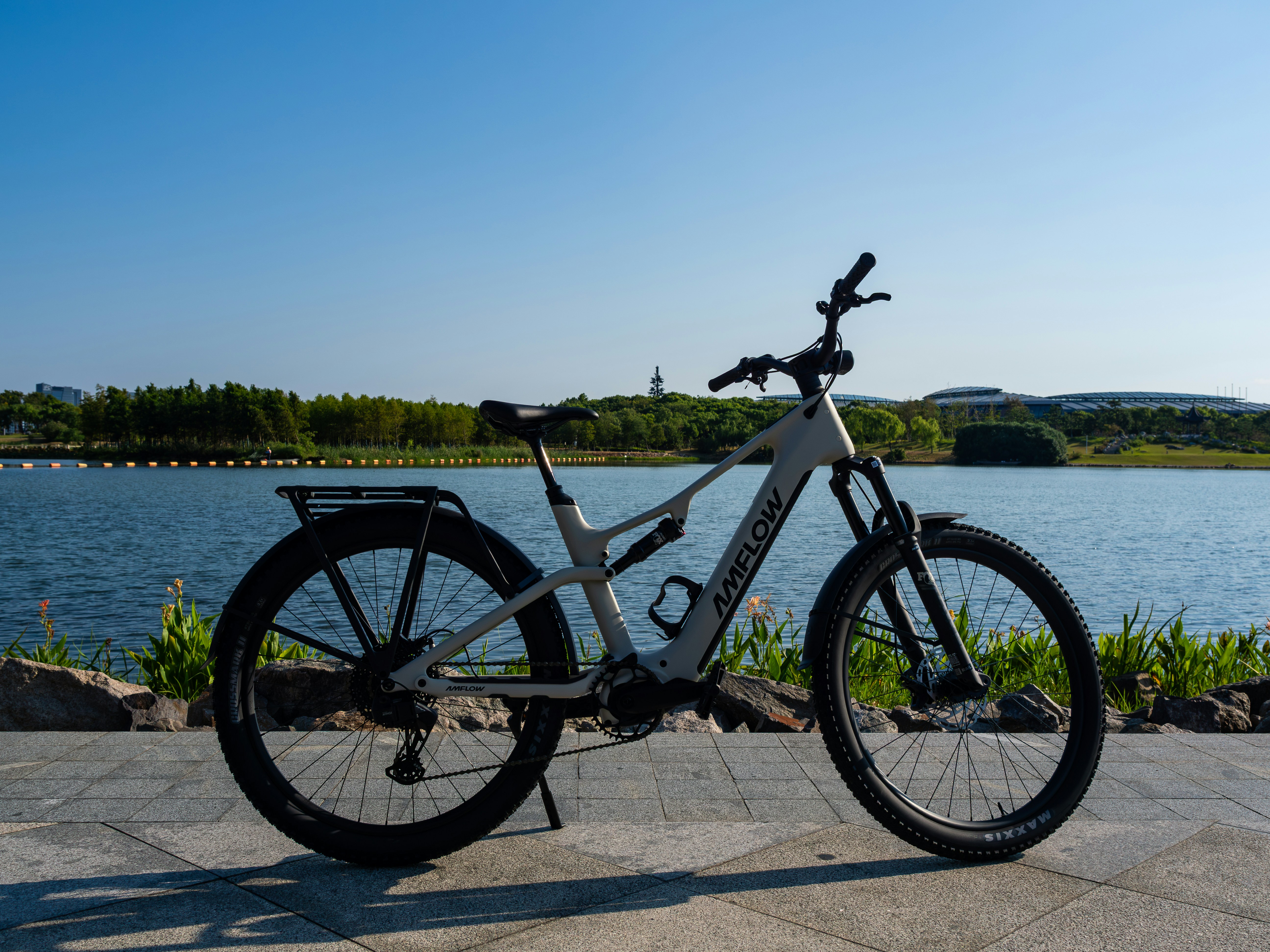 Electric bike framed beside a calm lake with a distant shoreline and greenery. A lifestyle/vehicle shot emphasizing the sleek frame and outdoor setting.