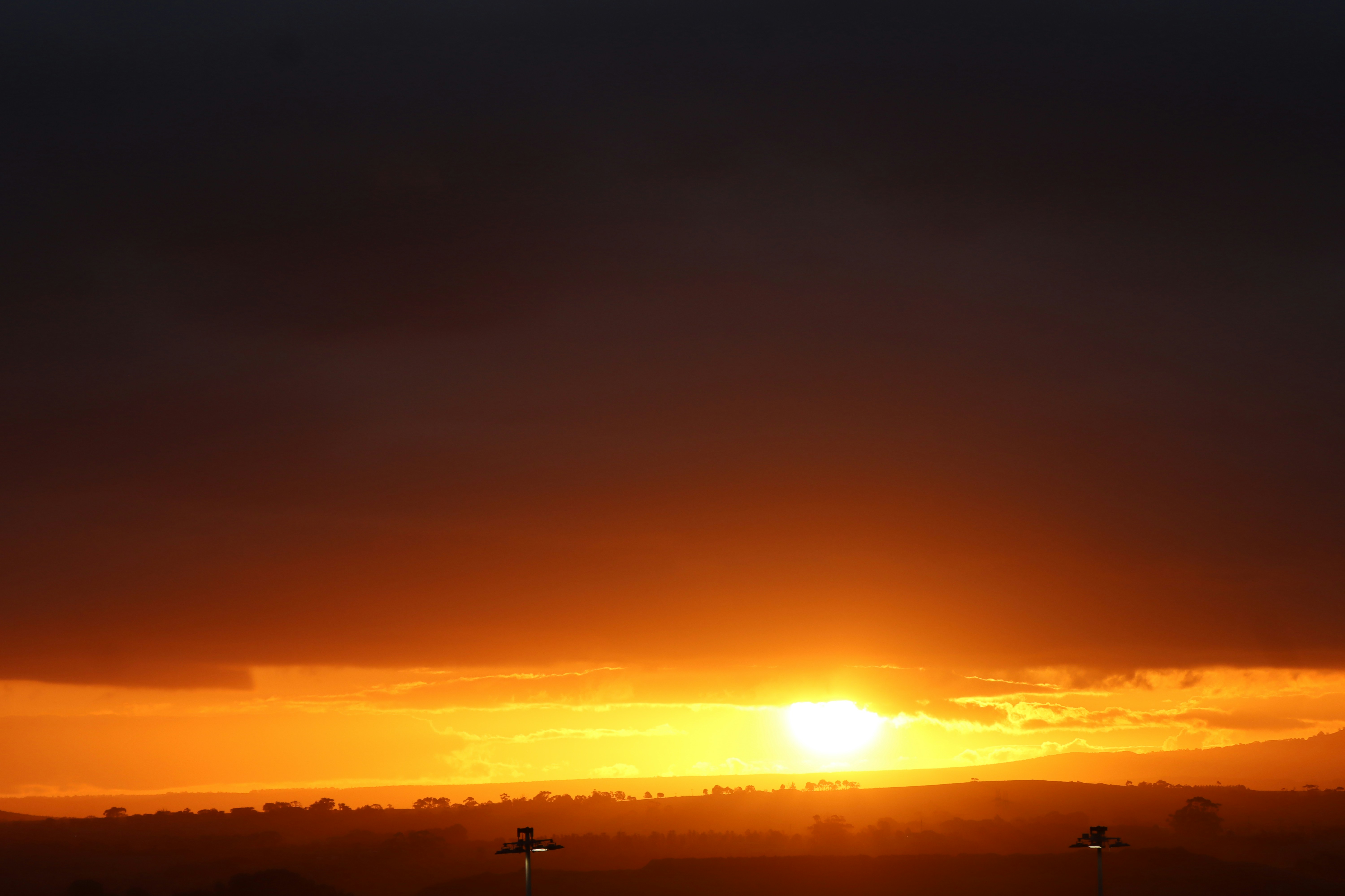 Fiery Horizon: A Quiet Sunset Over Distant Silhouettes