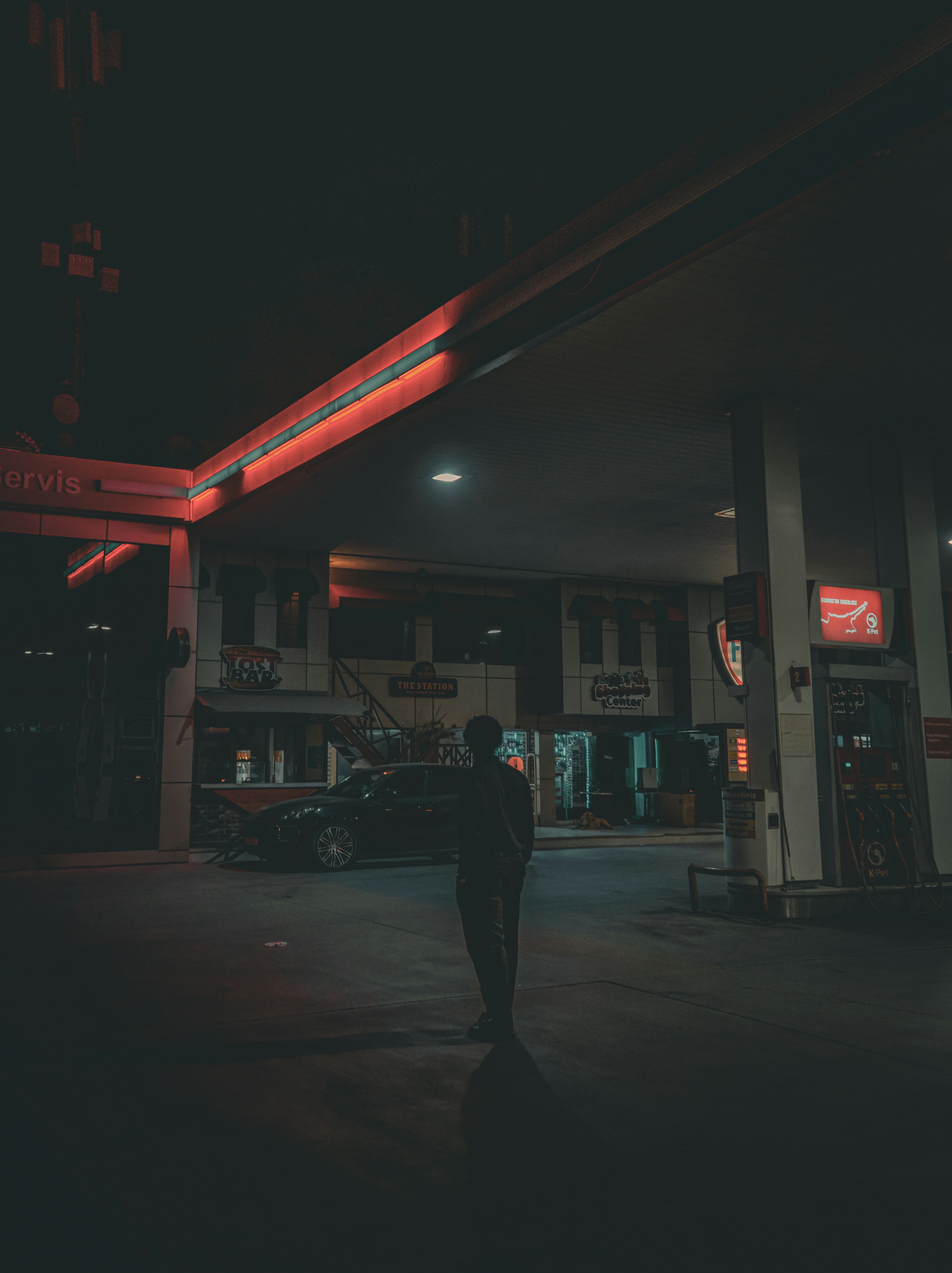 Neon Frontier: A Lone Figure at a Dim Gas Station