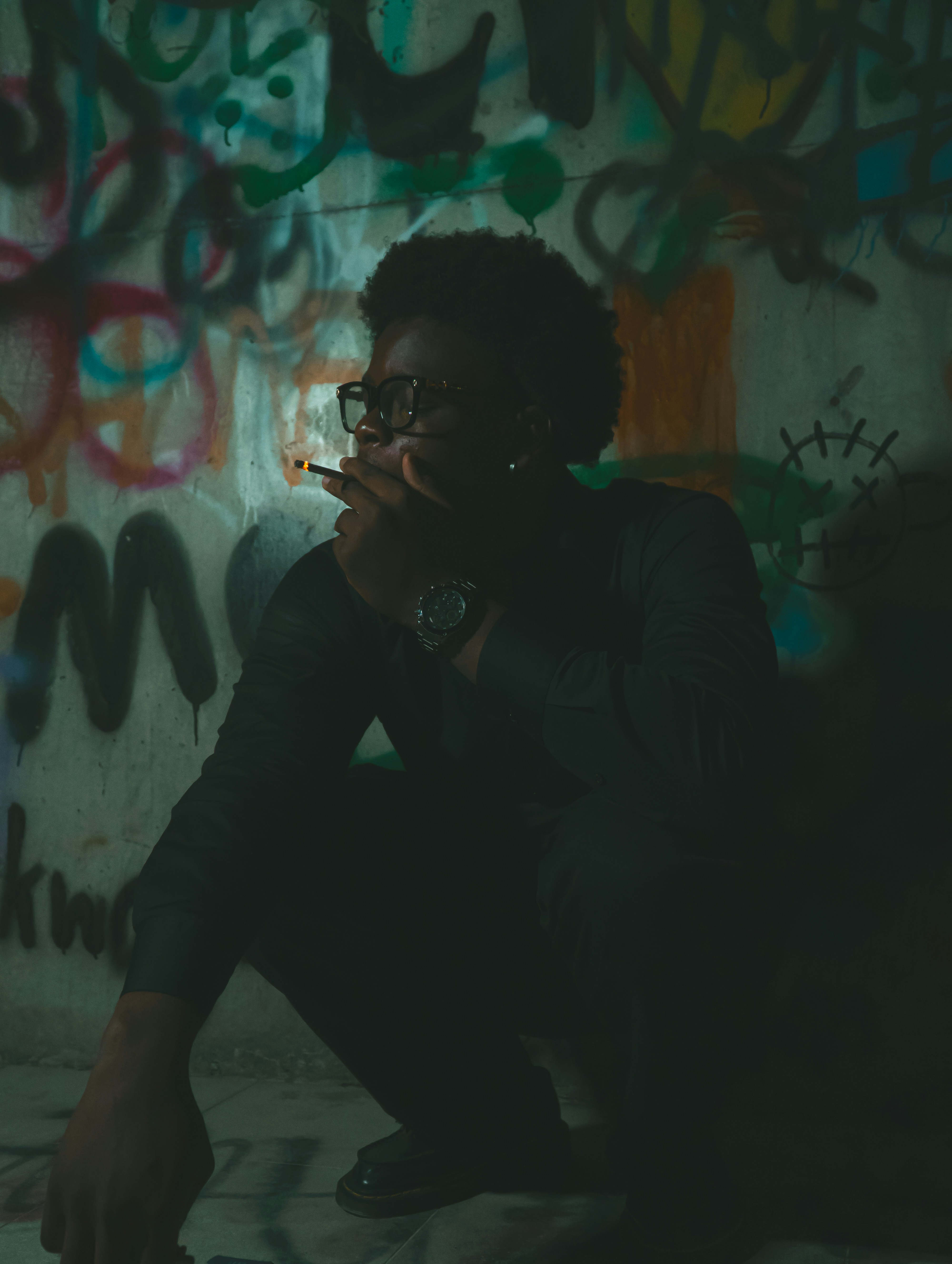 Cigarette glow in a graffiti-lit hush