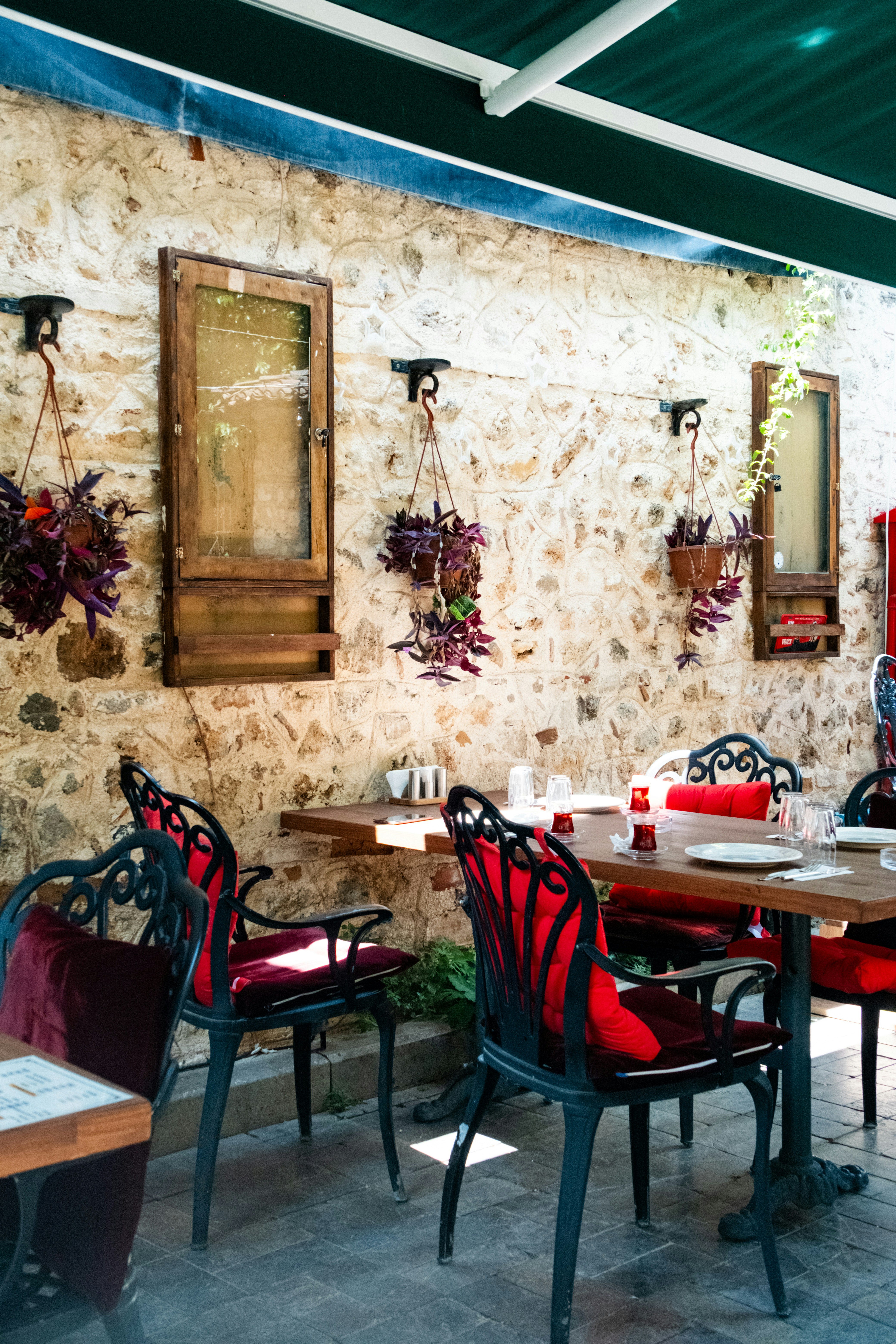 Sunlit Stone Patio Café with Lavender Hangings and Red Cushions
