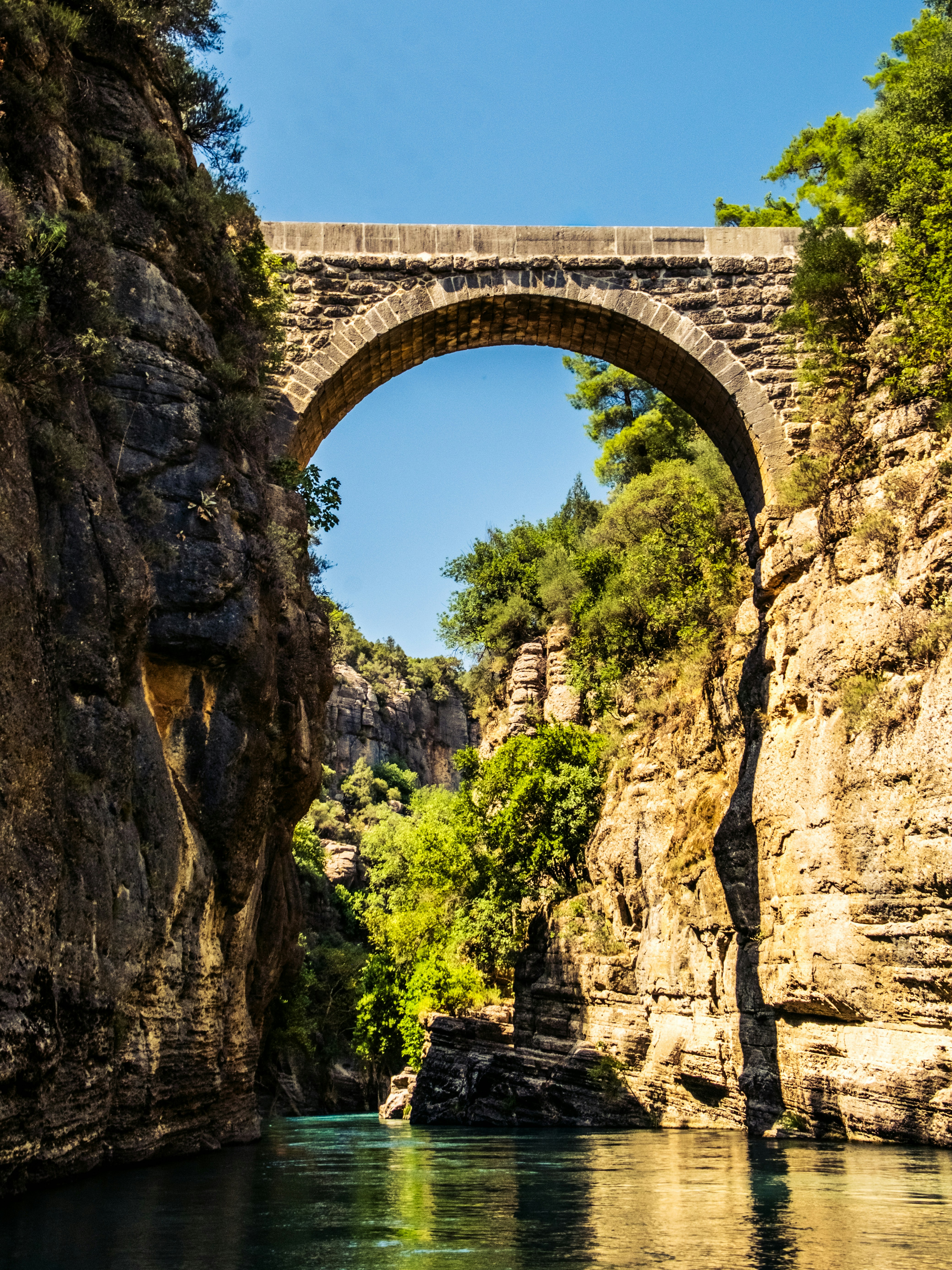 Arc of Stone Over River: A Majestic Cliff-Forged Bridge