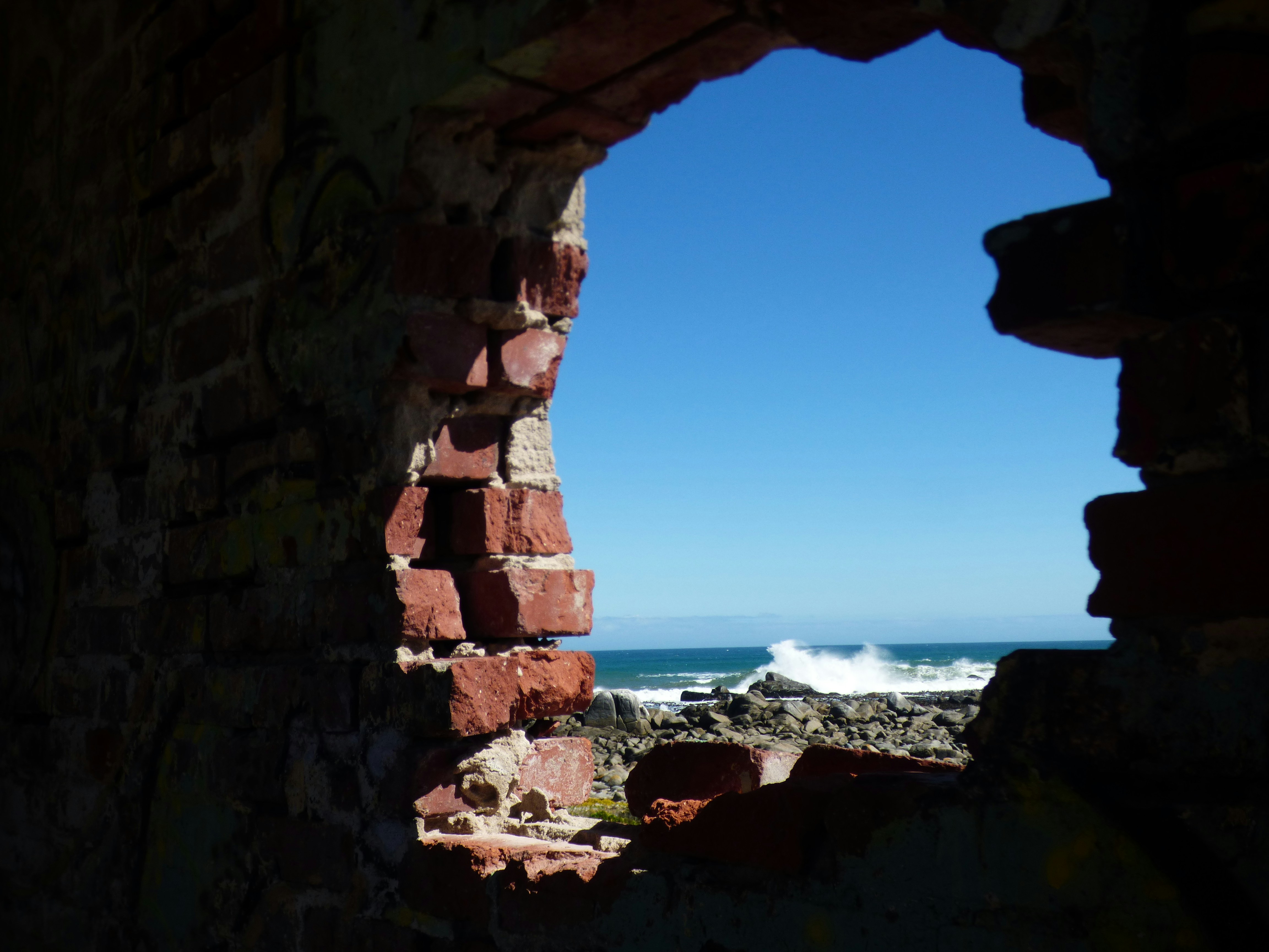 Shadowed Window to the Sea: Bricks Framing a Bright Horizon