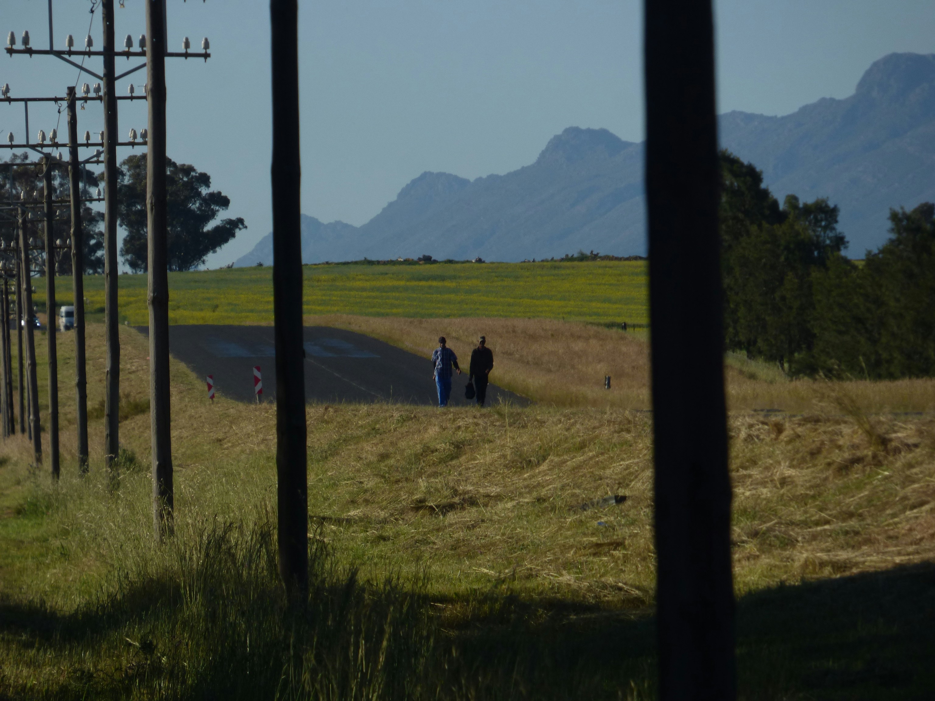 Quiet Field Walkunder: silhouetted figures near a fence with distant mountains