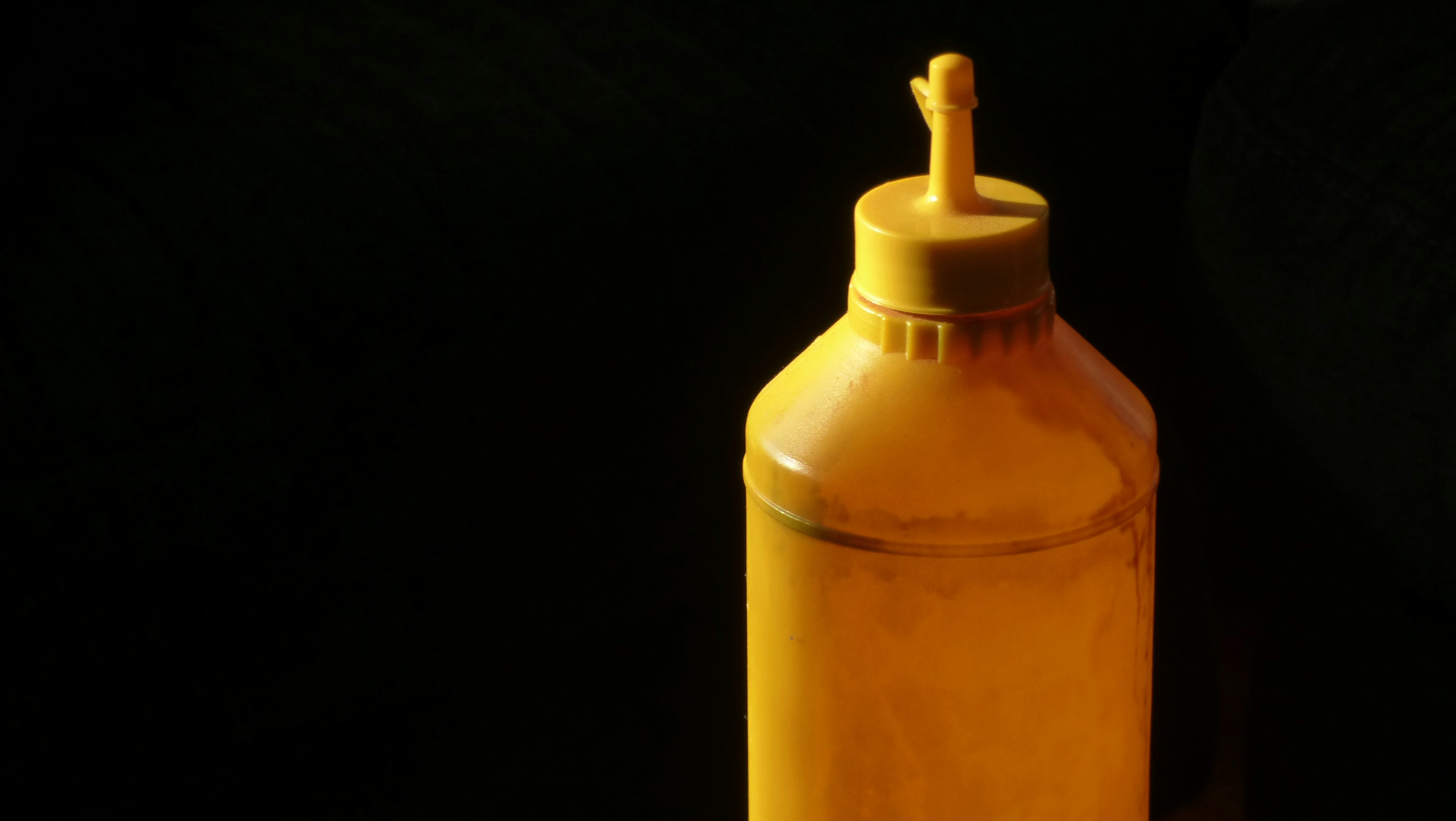 A yellow plastic squeeze bottle against a dark background