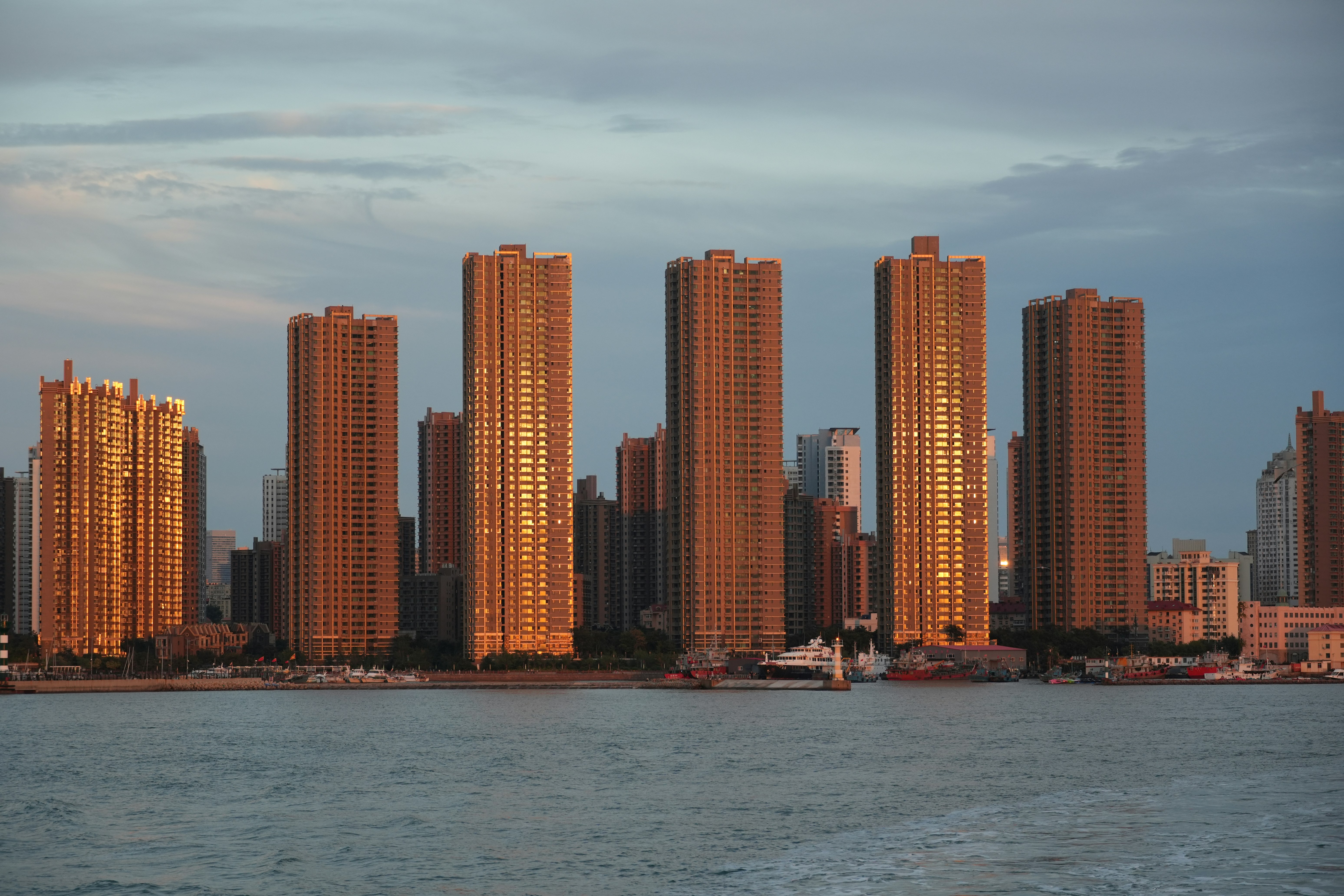 Sunlit Skyscrapers: Gold-Tinted Waterfront Skyline at Dusk