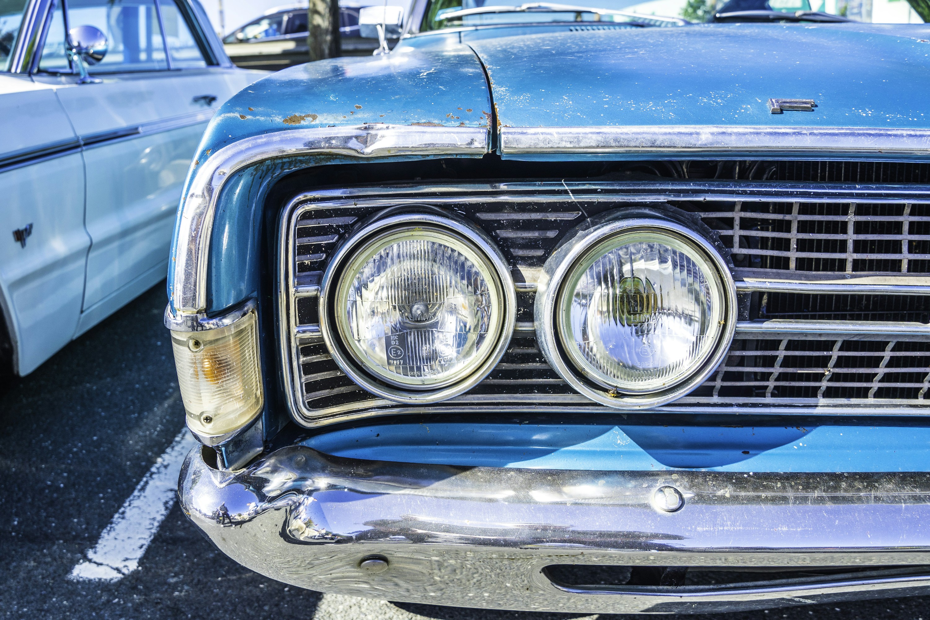 Chrome Echo: A Blue Classic Car’s Front Grille in Focus