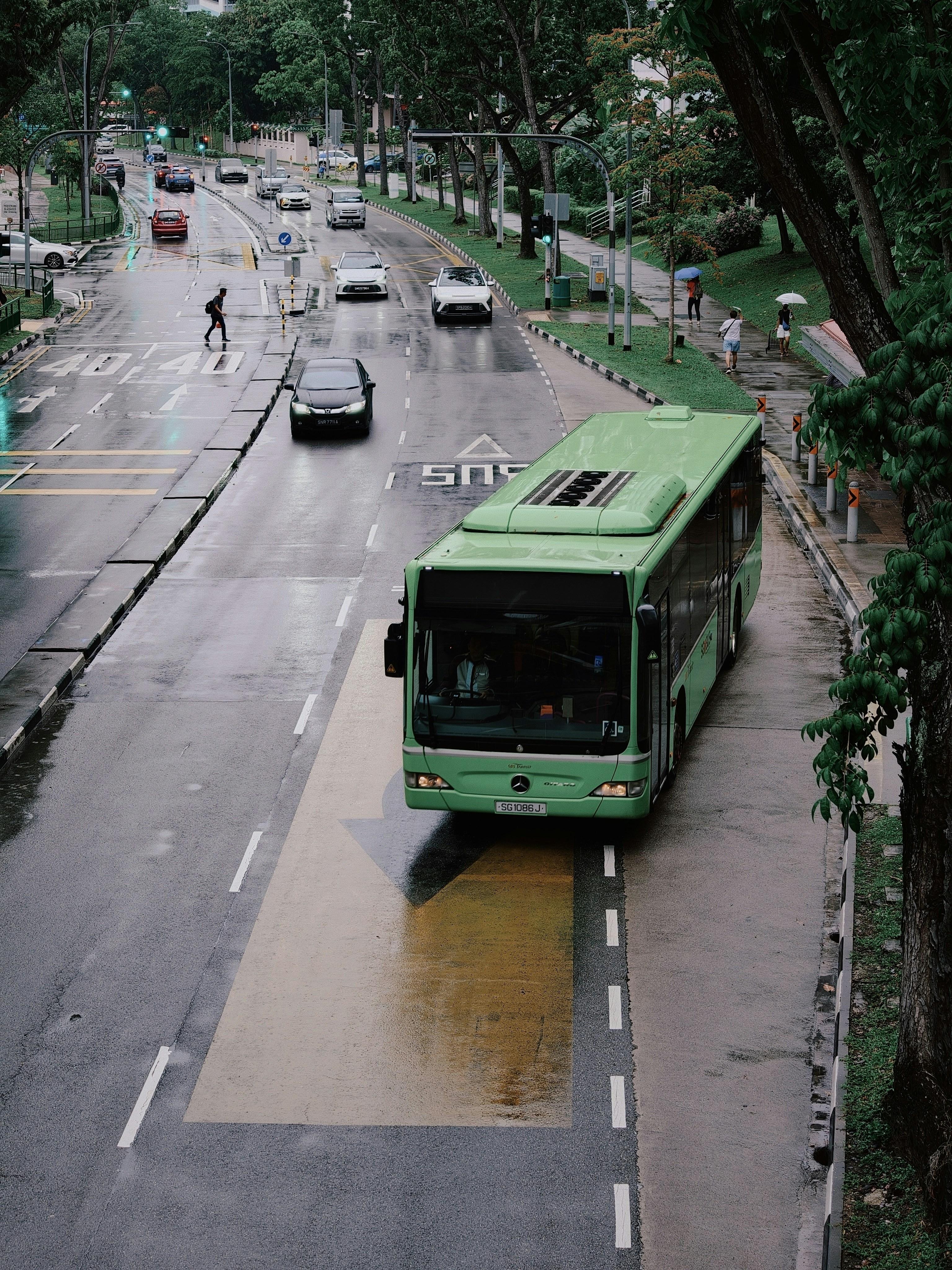 Green City Bus Rides Through Rain-Slicked Avenue