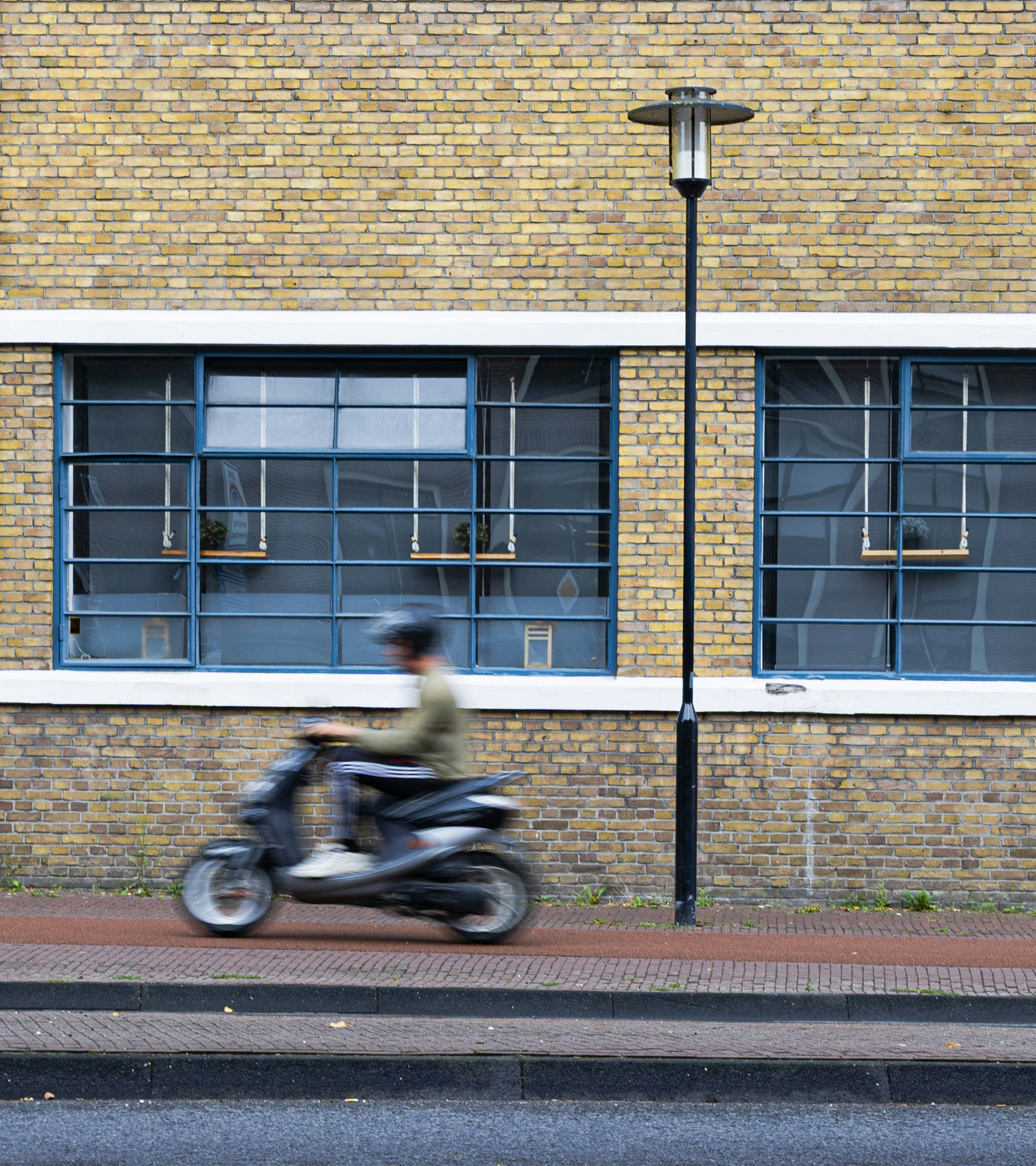 Motion Through the Street: Blurred Rider in Front of a Brick Factory Wall