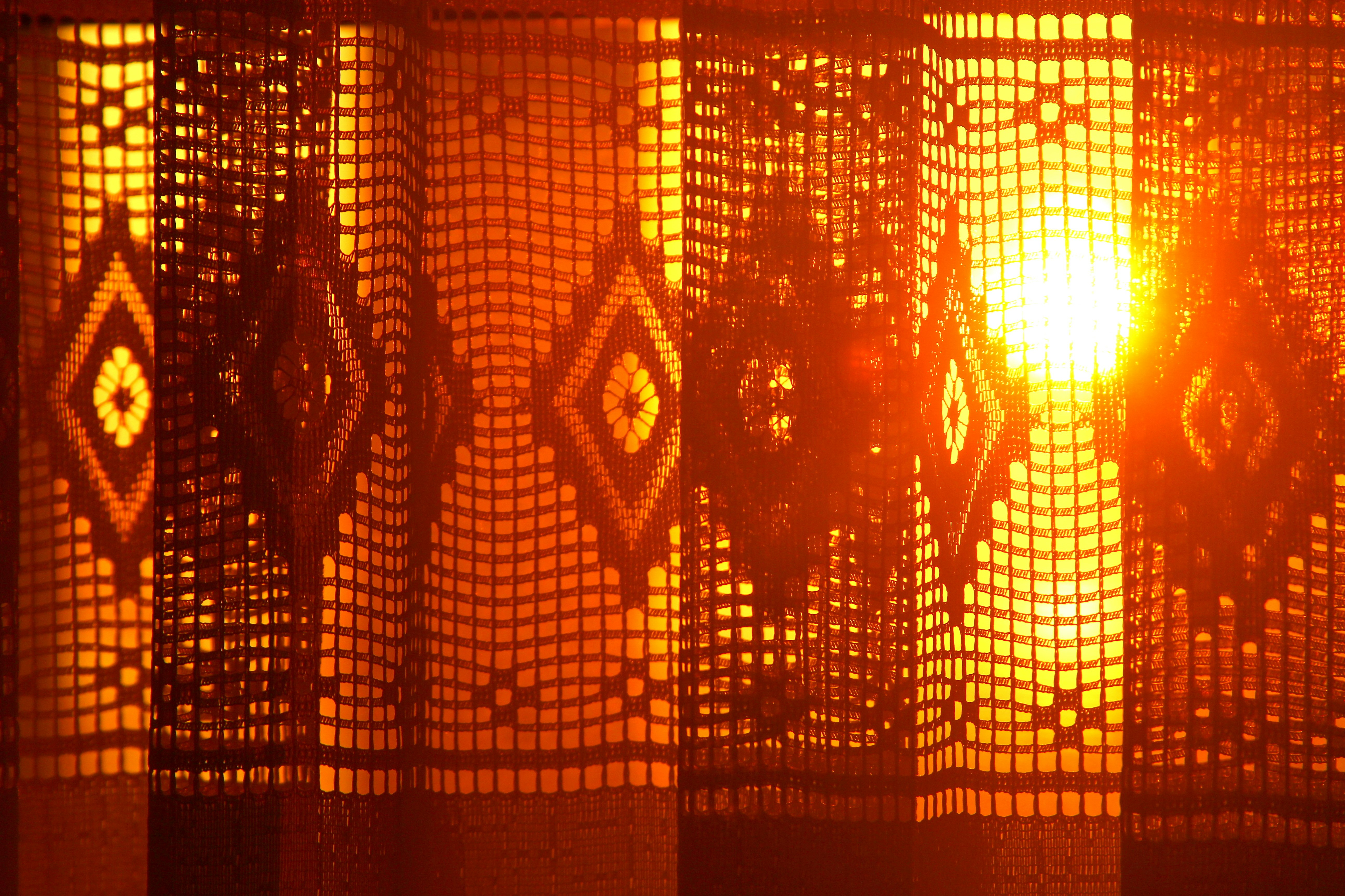 Sunlit Lace: Geometric Curtain Silhouette with a Fiery Glow
