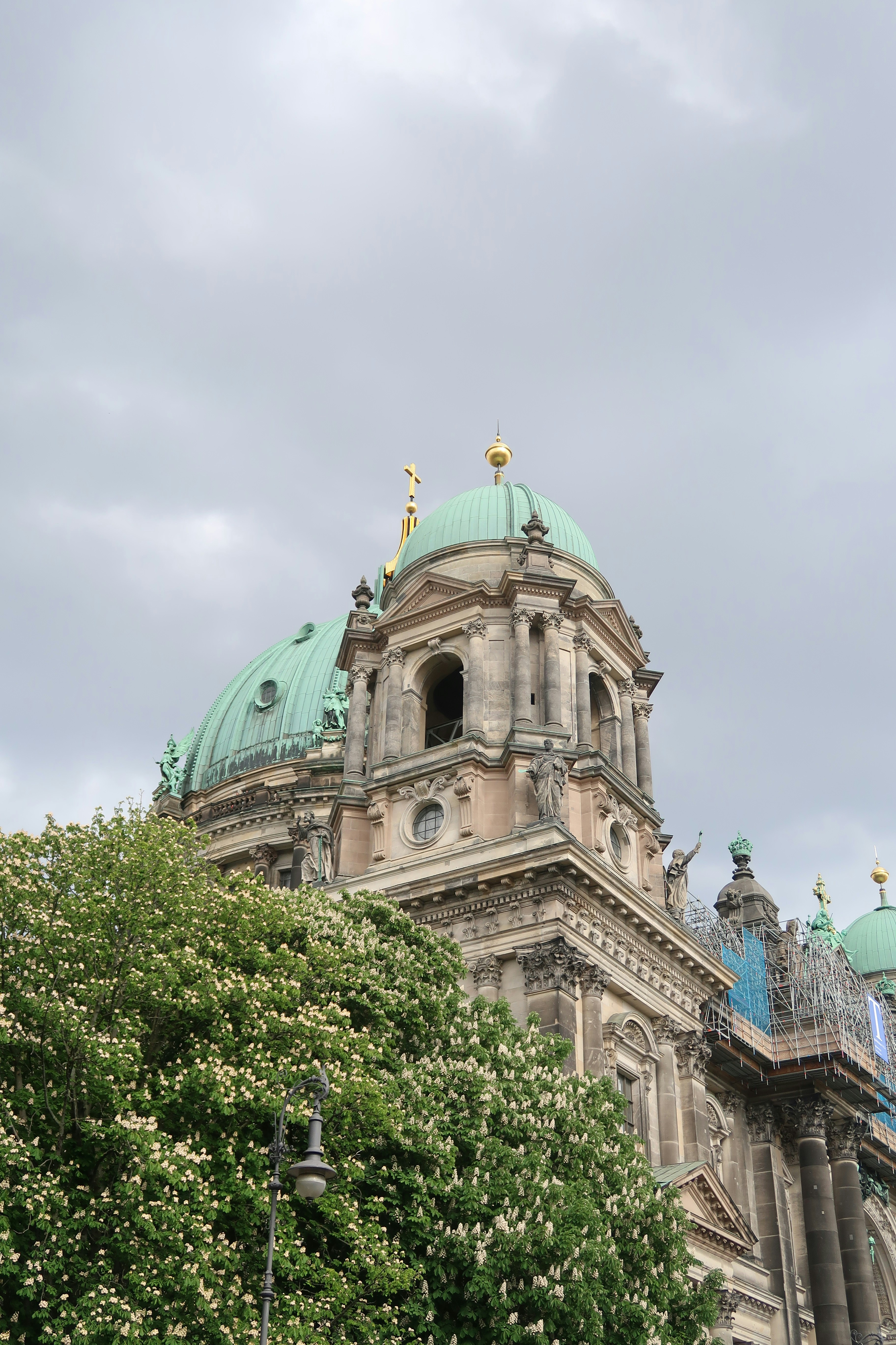 Green Domes, Stone Facades: Prague Cathedral Ensemble Rising Over Blossoming Foliage