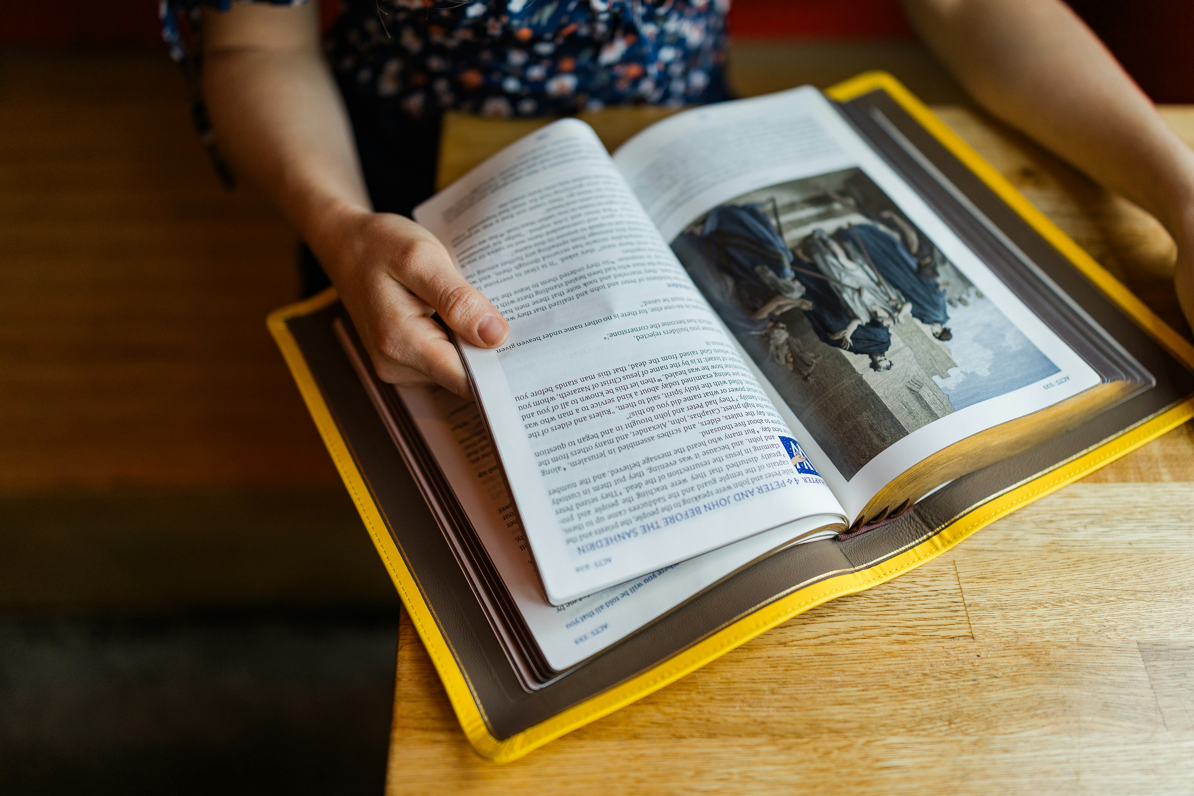 Hands on a yellow-edged tablet case framing an open book