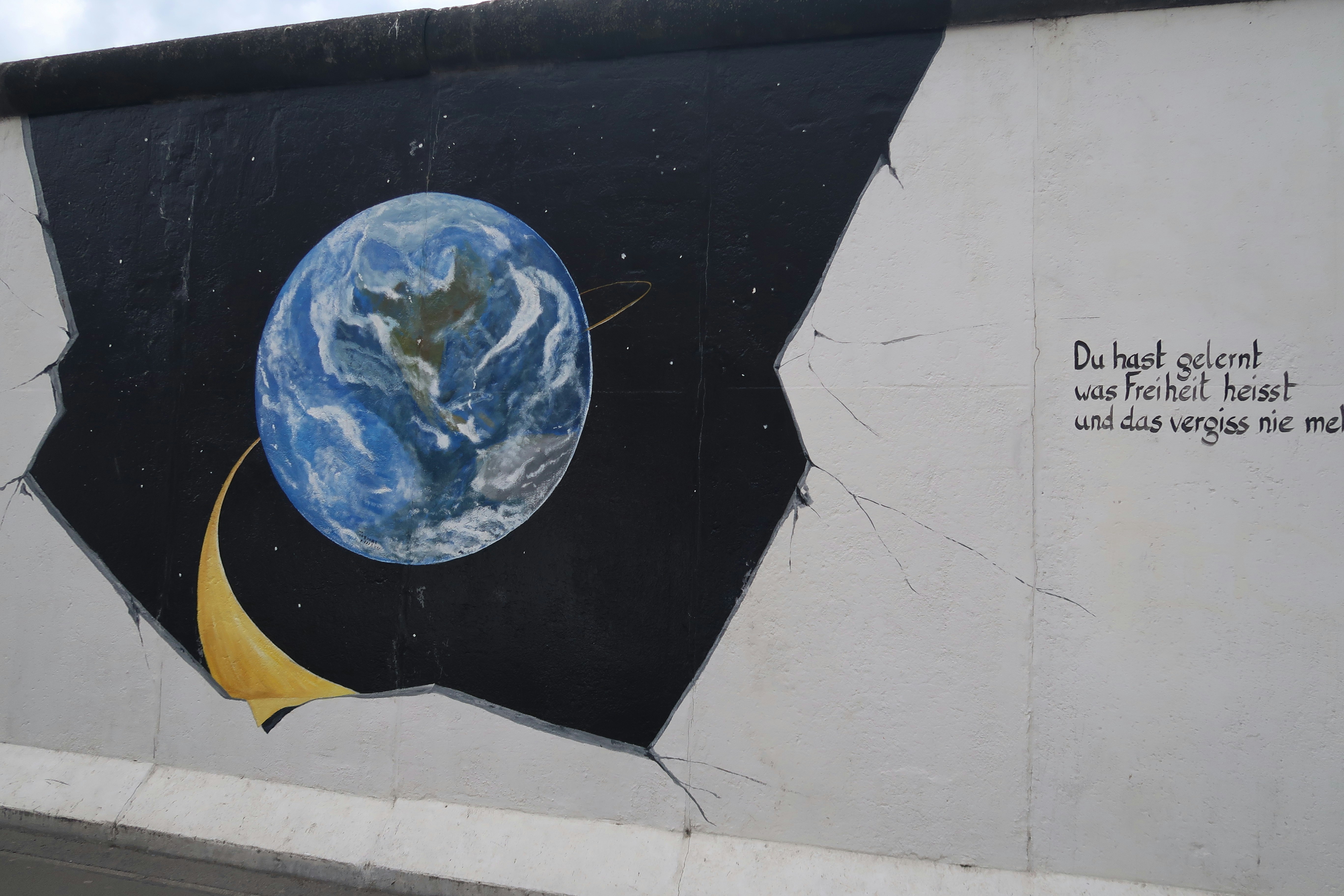 Earth and Crescent Night: mural unveiling through a fractured wall