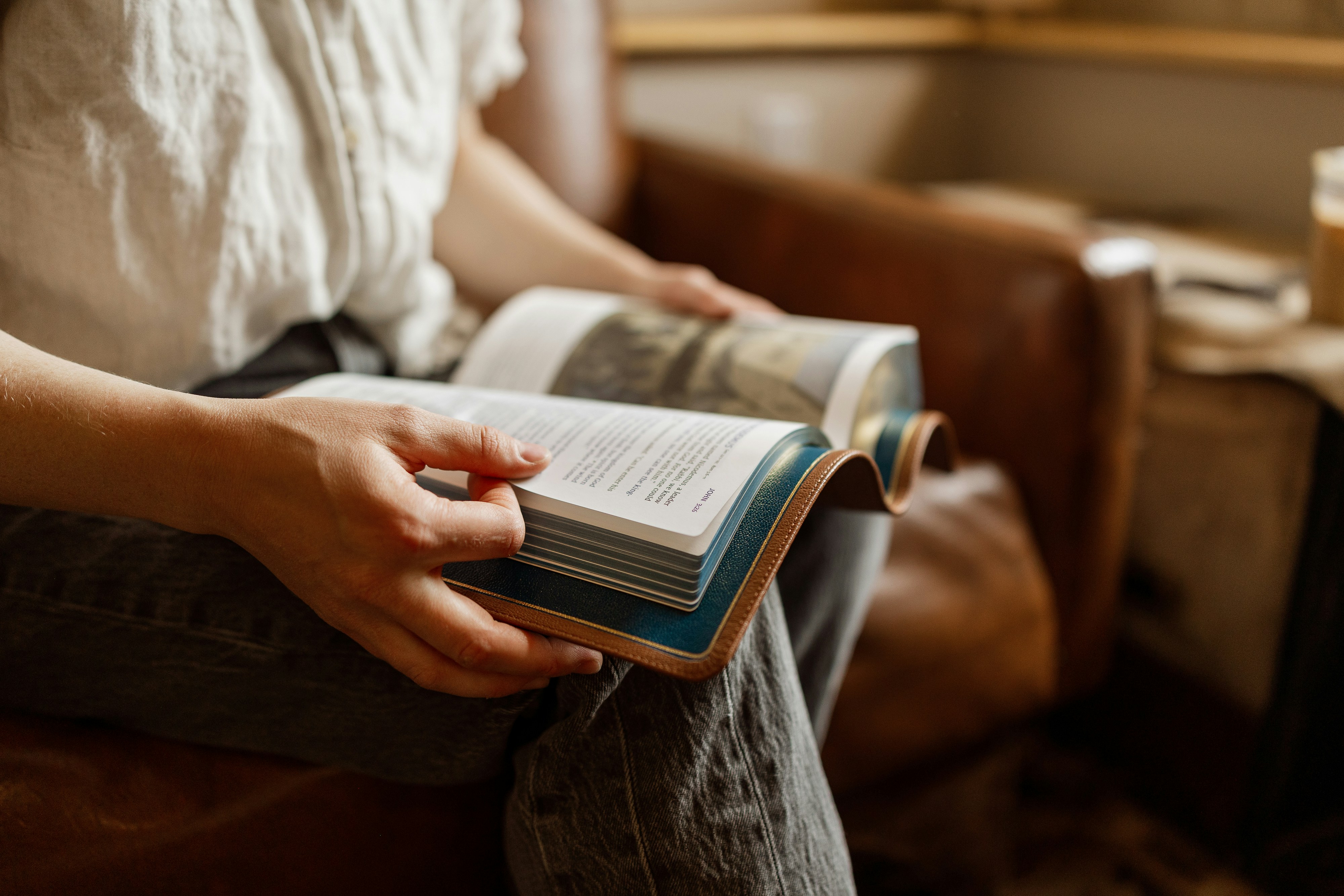 Quiet Reading Moment: Hands Turn the Page of a Book on a Cozy Sofa