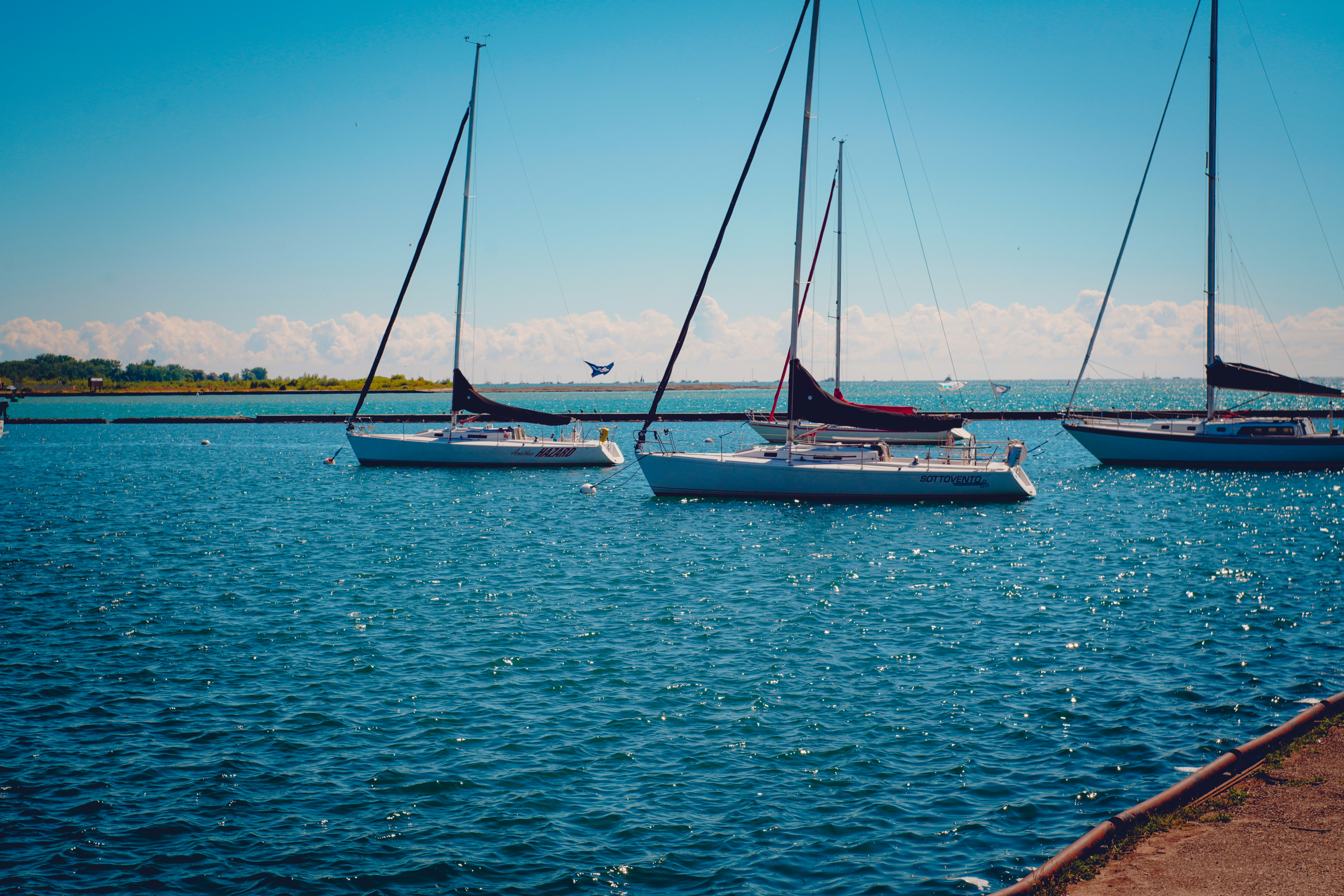 Sailed Silhouettes: Three Leisure Boats Quietly Rest on a Blue Seascape