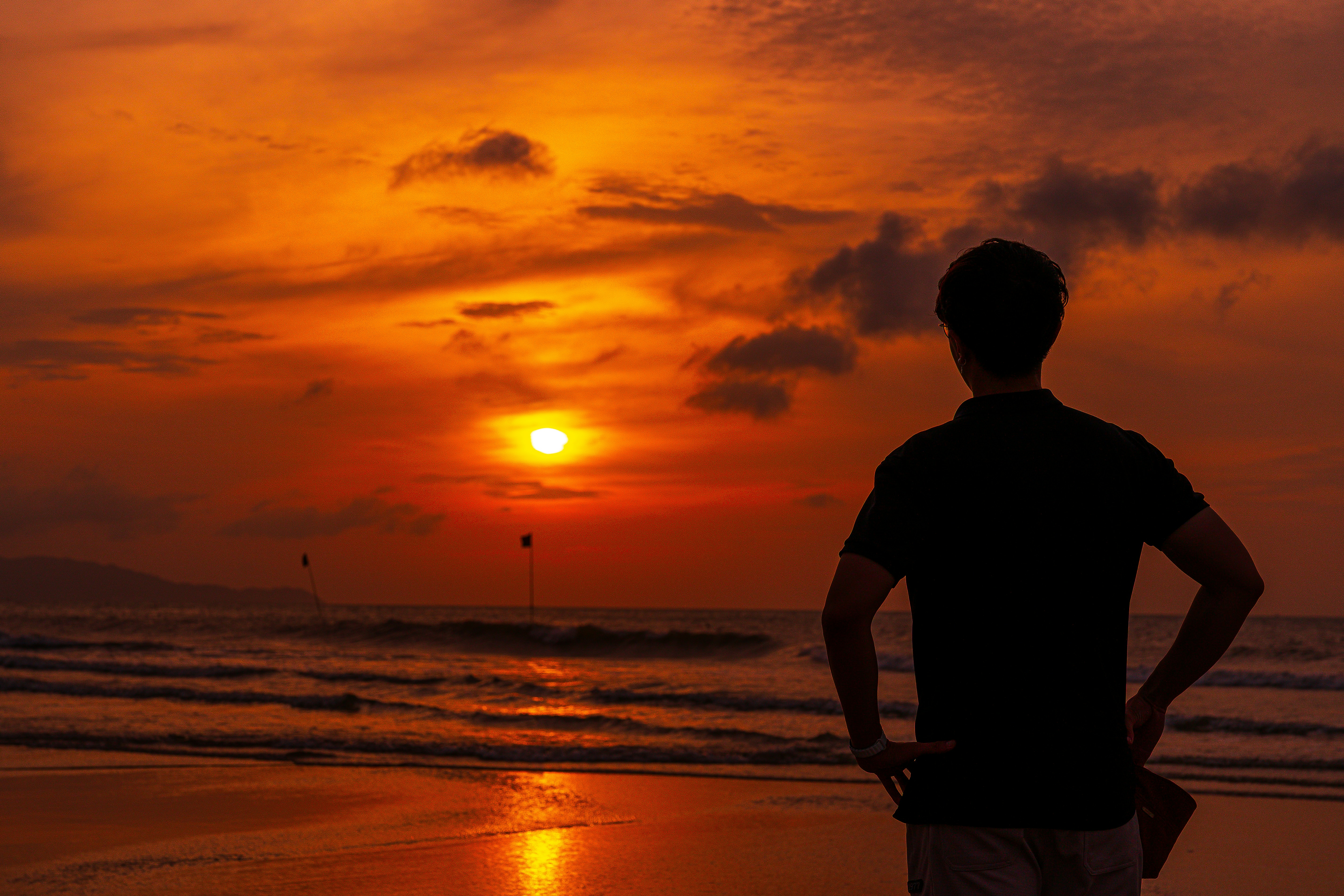 Silhouette at Sunset: A Lone Observer by the Tidal Line