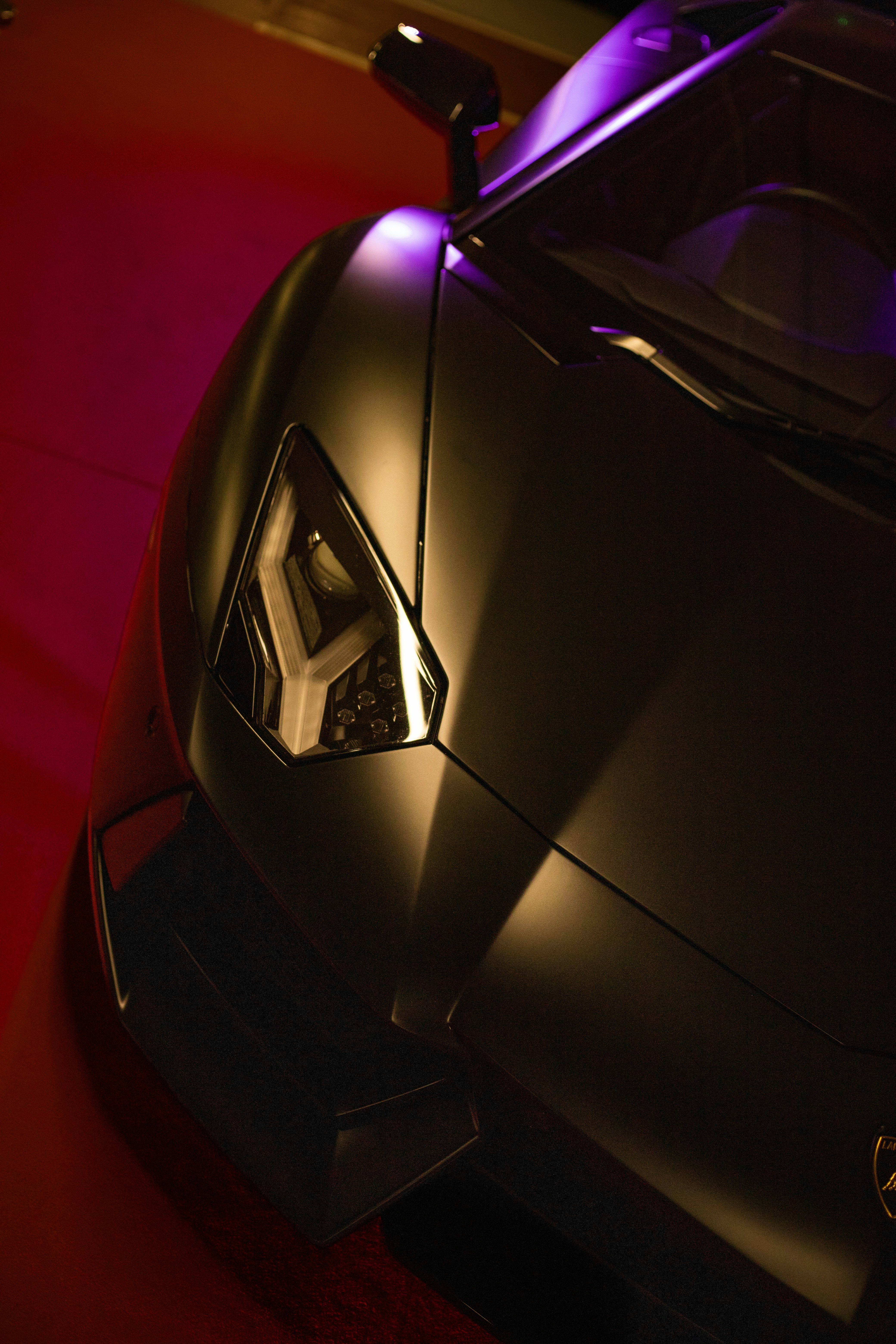 Matte Fury: The Front View of a Dark Hypercar Under Neon Glow