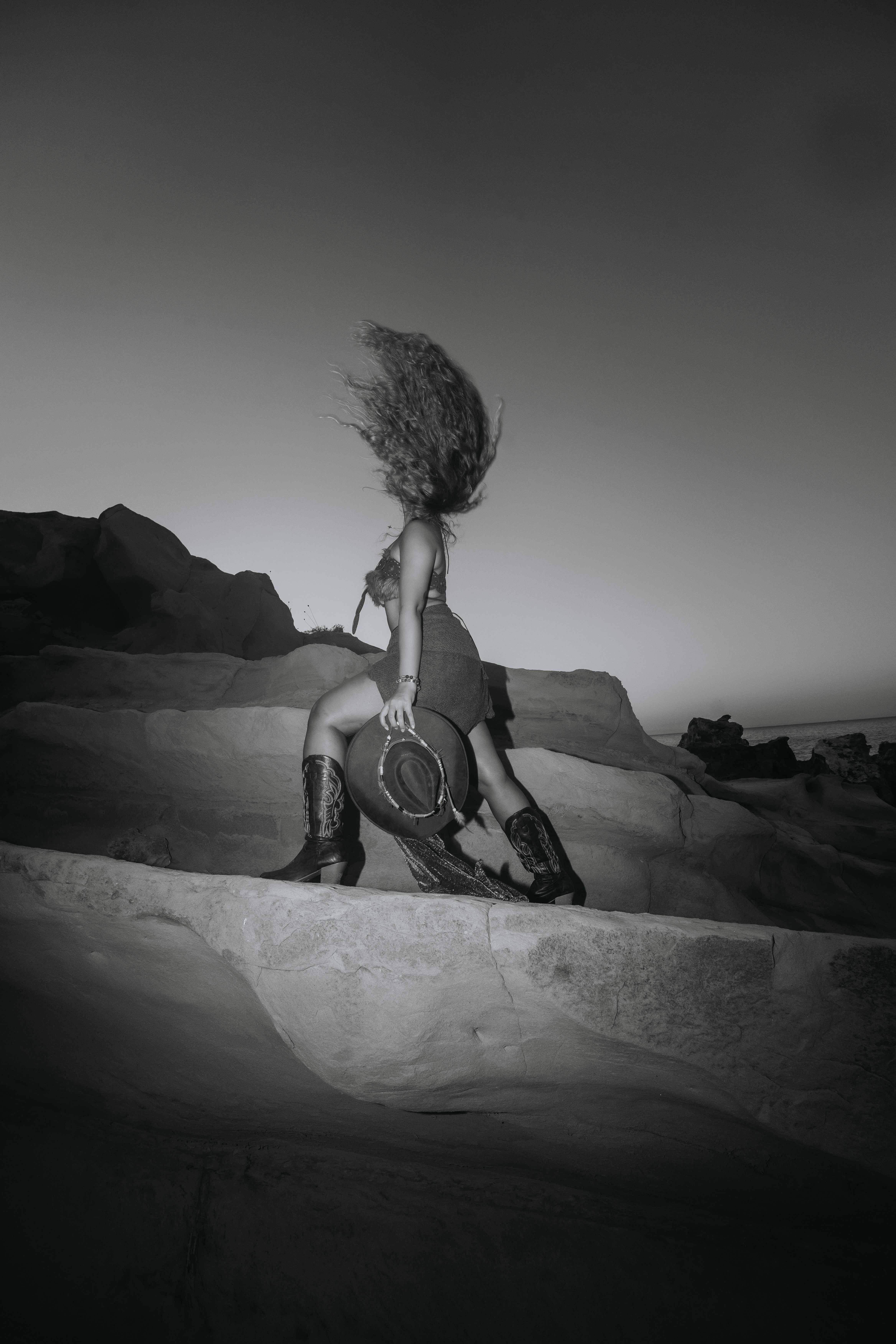 Windward Gaze: A Lone Figure Ascends Rock and Wind
