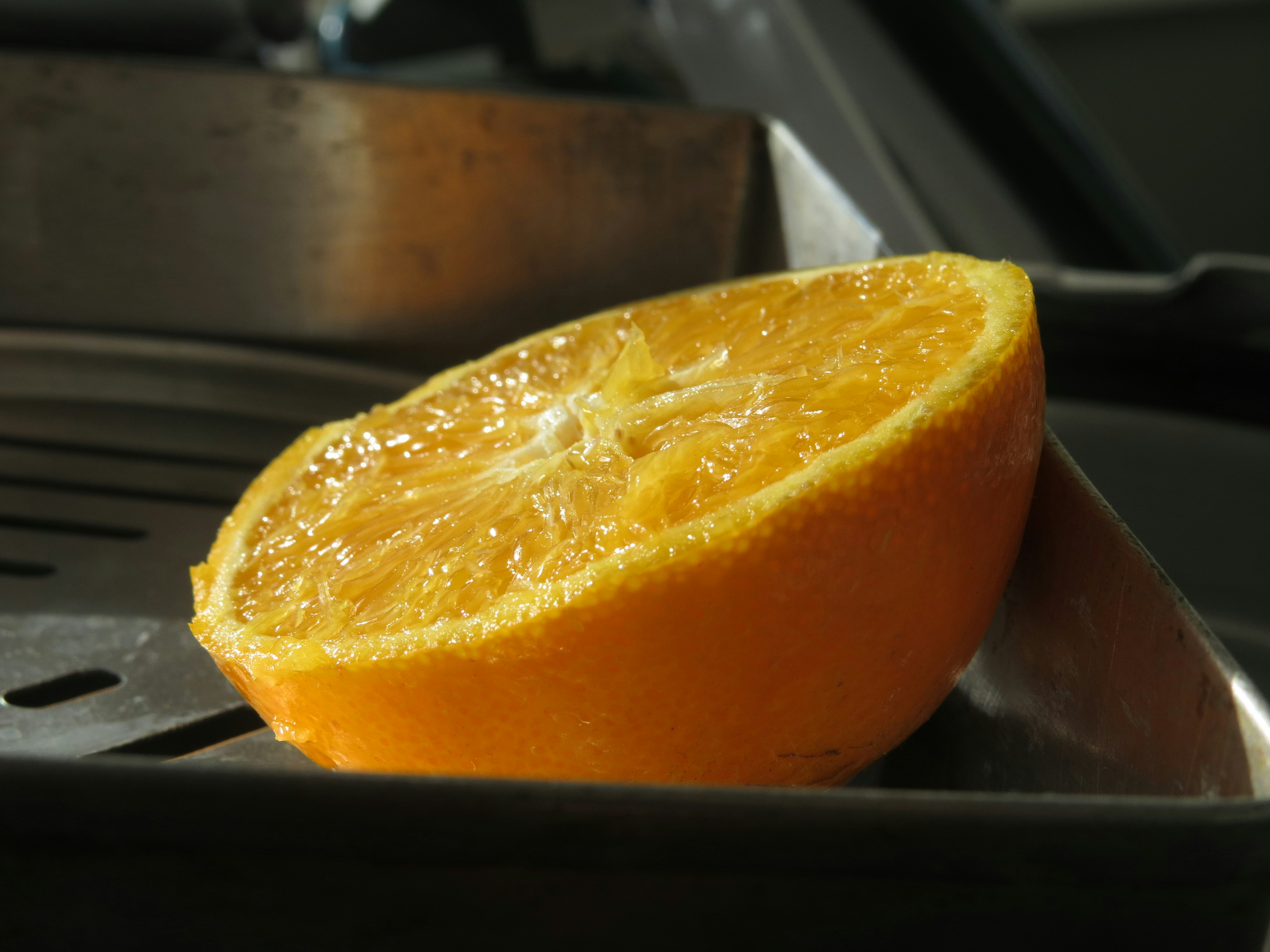 Citrus on a Sheet: An Orange Half Settles Into a Steel Tray