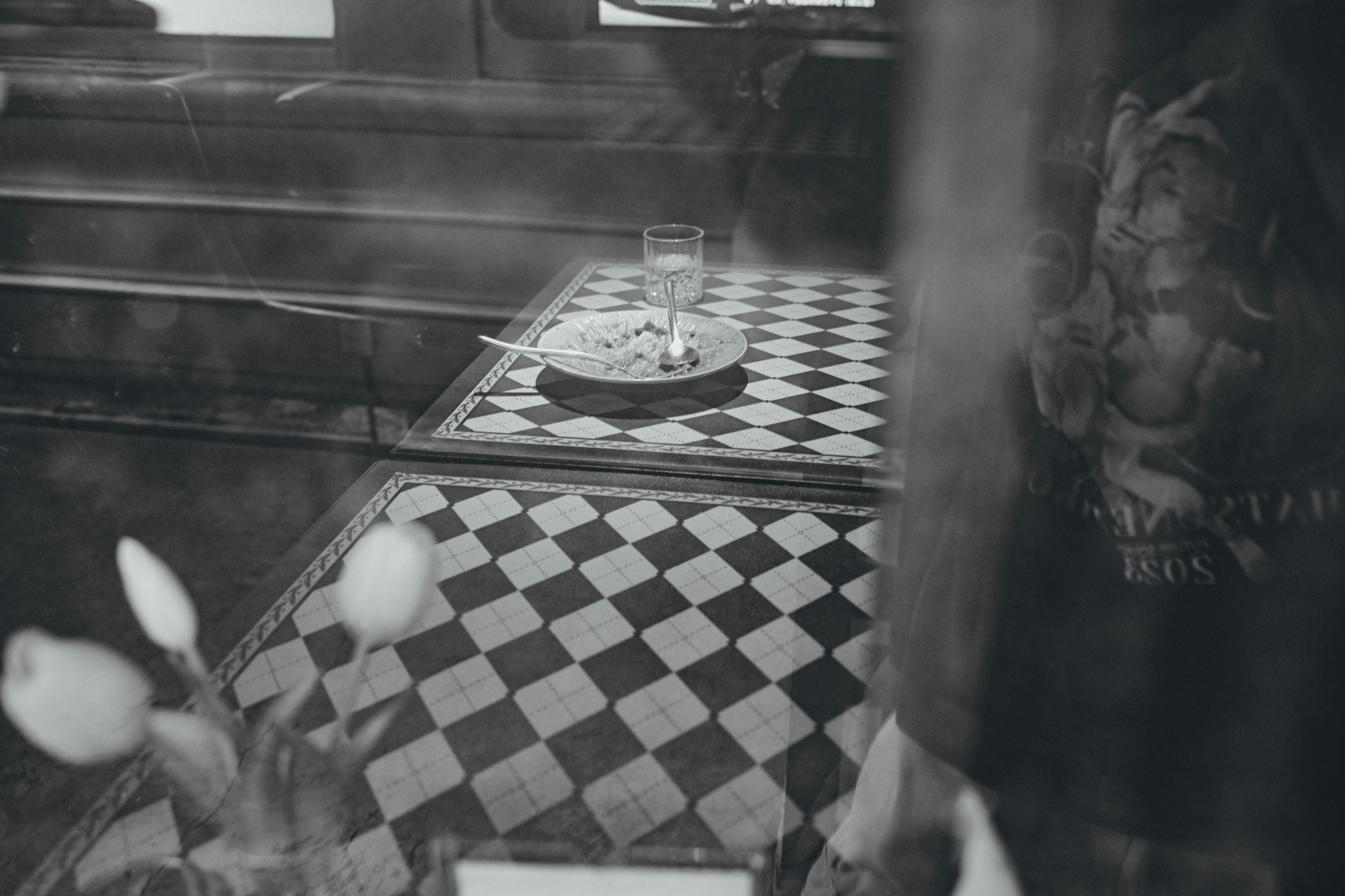 Empty Glass, Checkered Table, and Ghostly Reflections in a Quiet Cafe