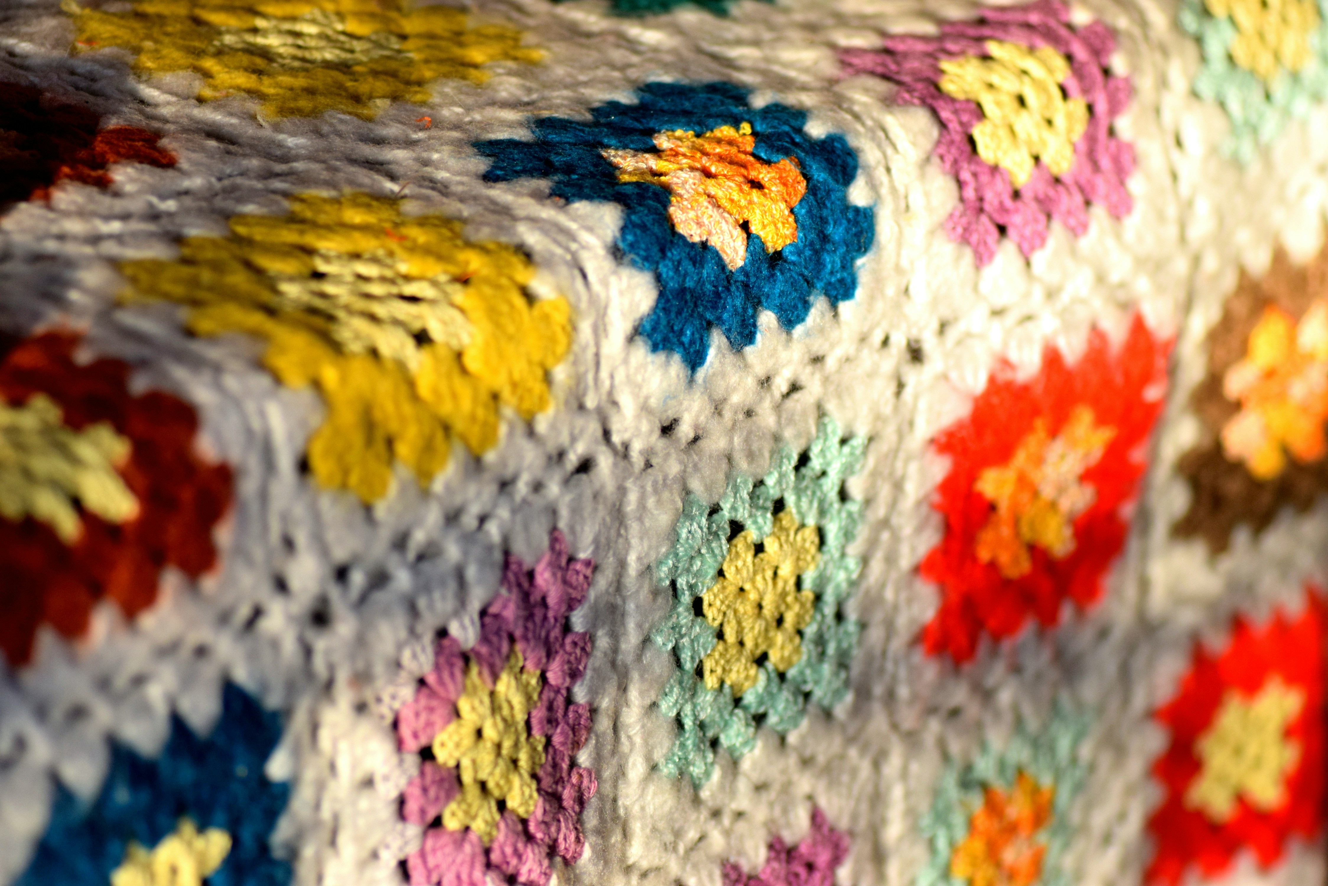 Colorful Crochet Mosaic: A Close-Up of Granny Squares on a Soft Fabric Sheet