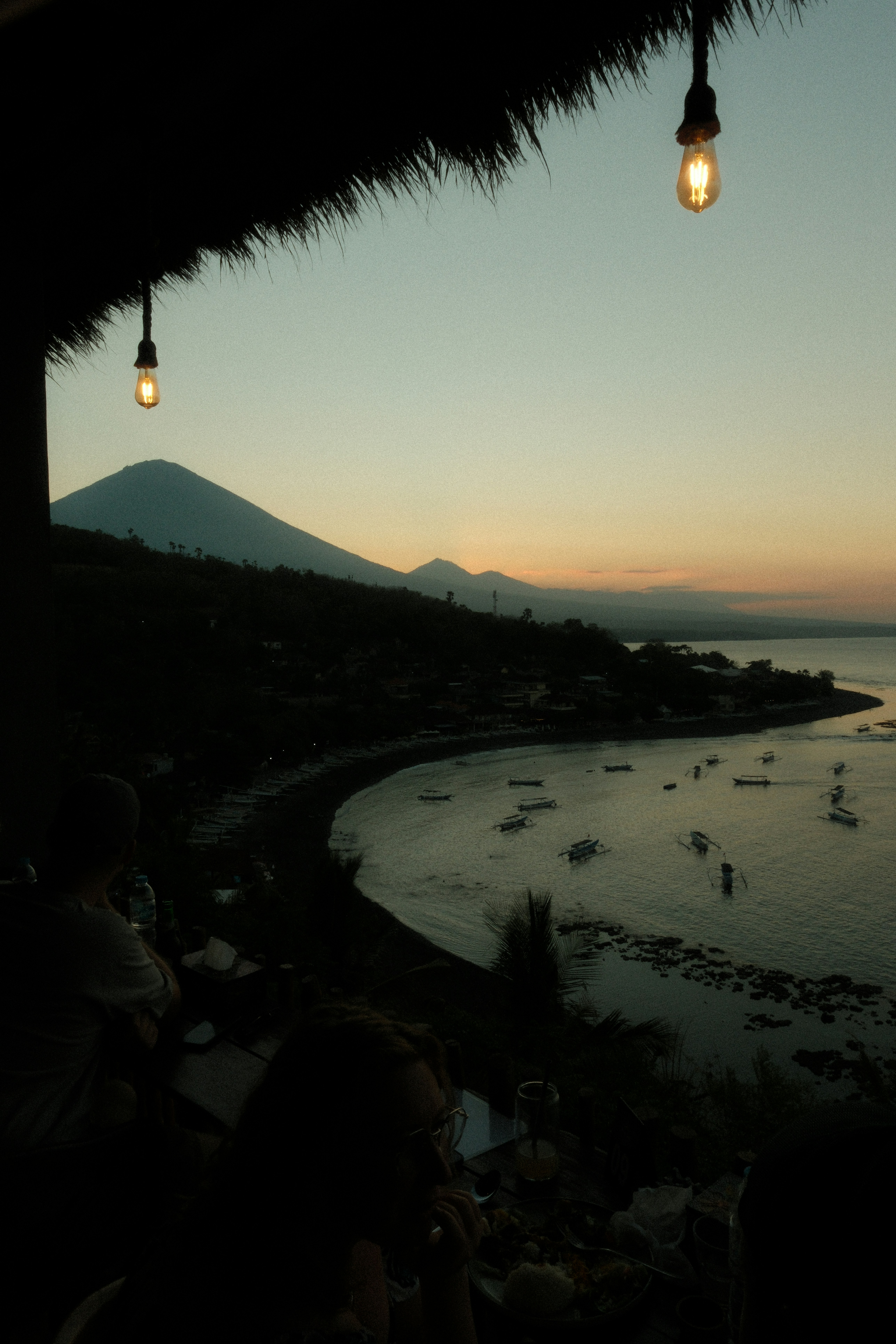 Sunset Over the Cove: Lanterns, Coastline, and Silhouettes