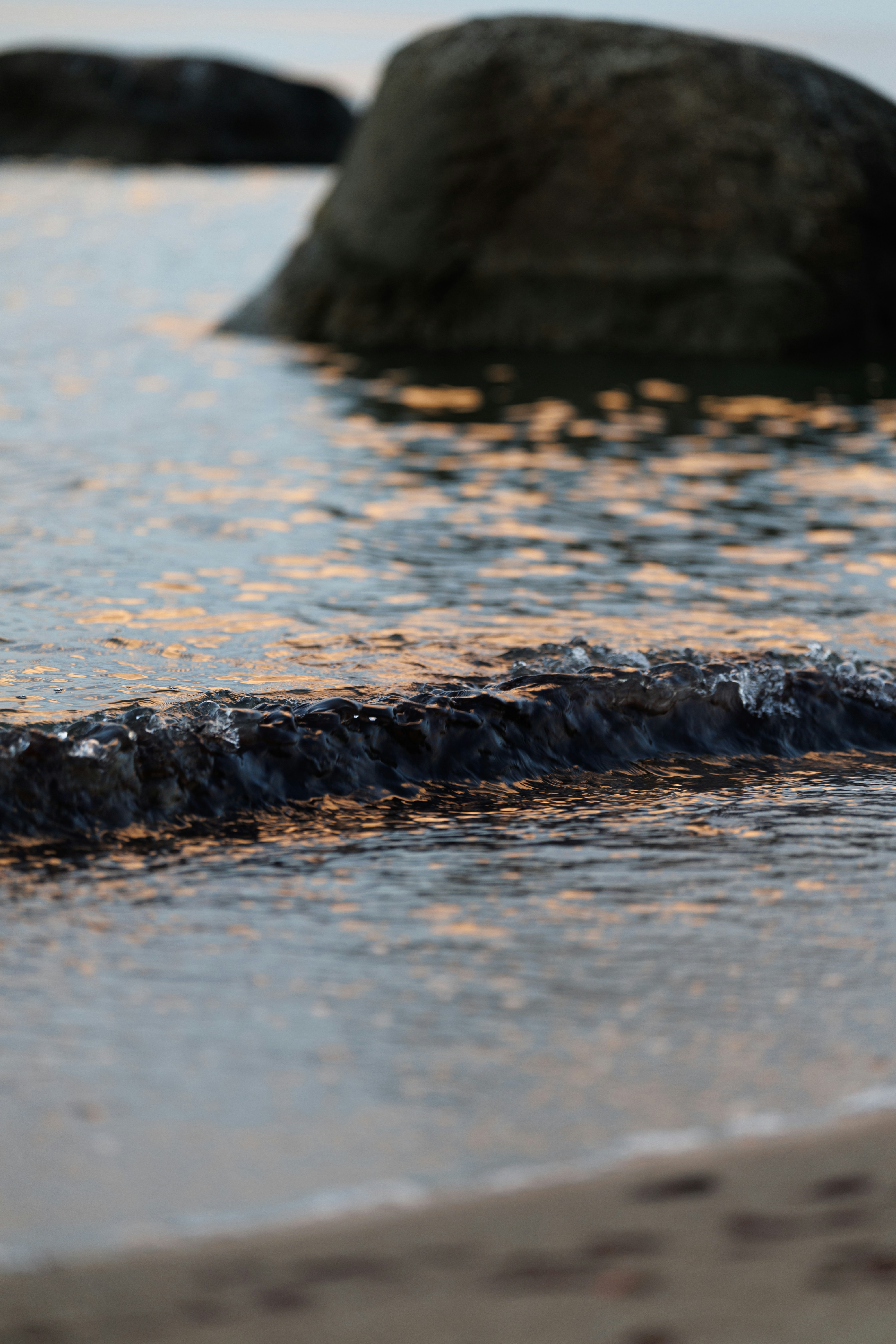 Sunlit Shoreline Bubbles: Quiet Ripples by the Rock
