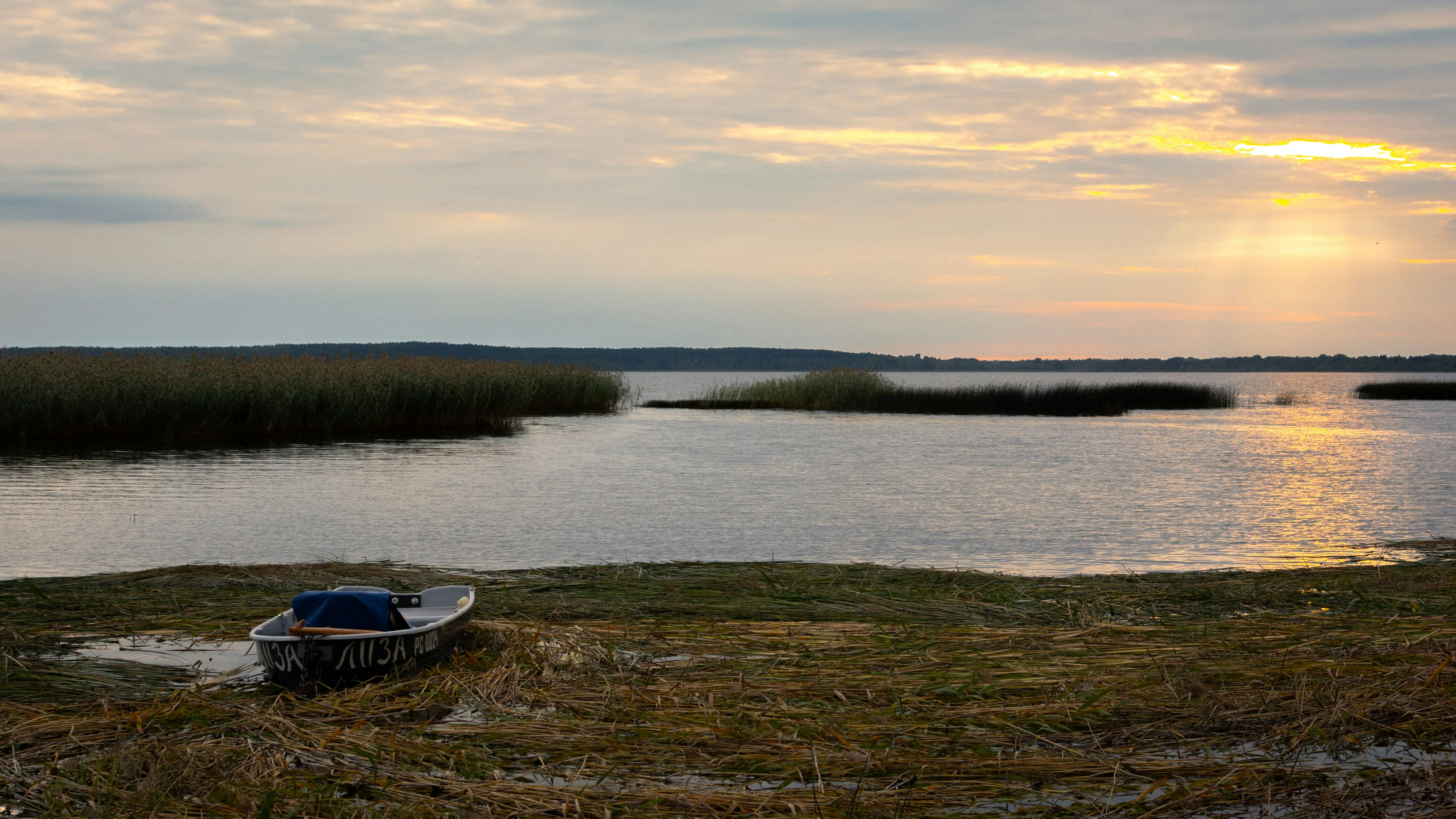 Midday Quiet: A Boat Resting on Tidal Sediments by Sunset Reed Flats