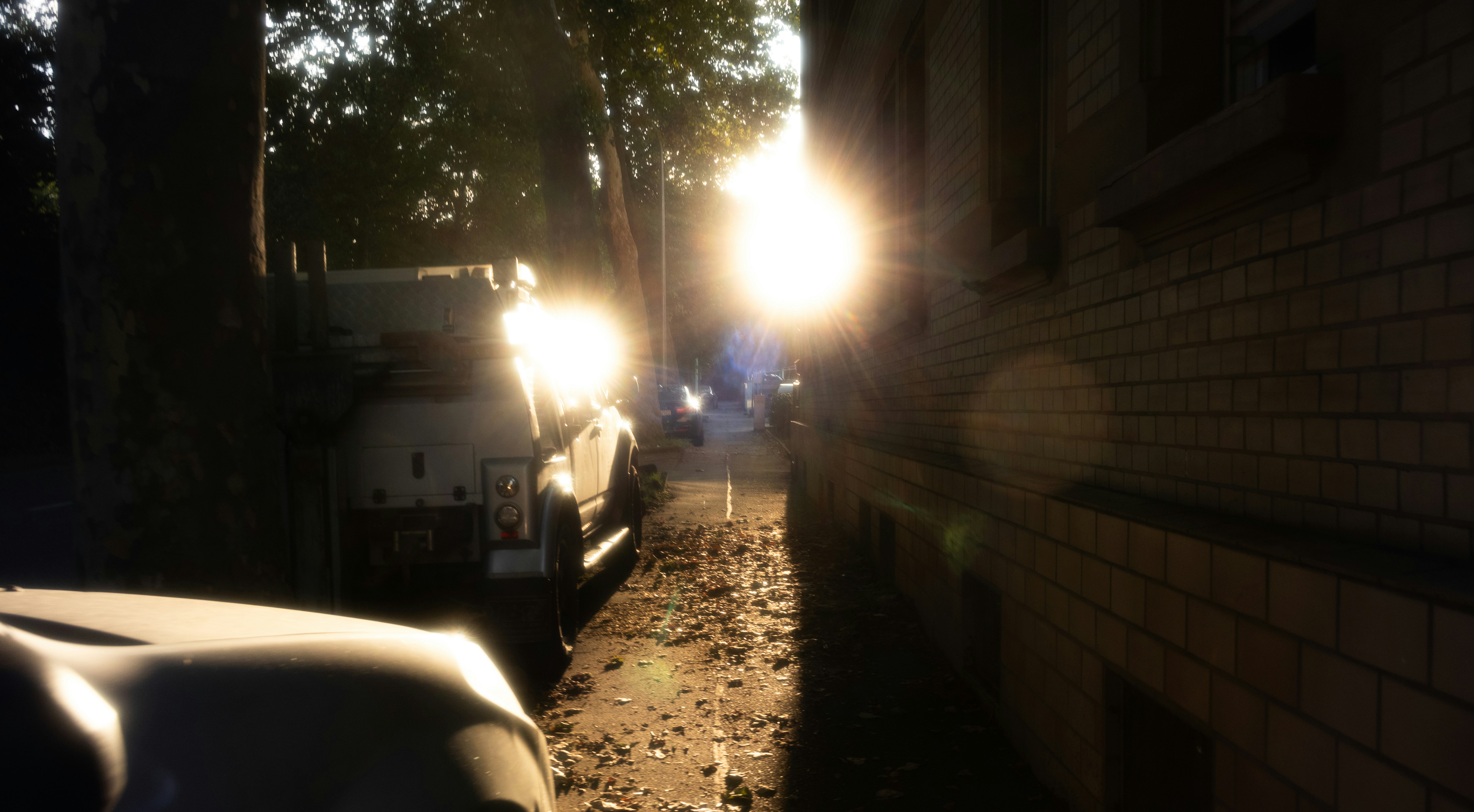 Backlit Alleyway: Glare, Trucks, and a Narrow Path of Light