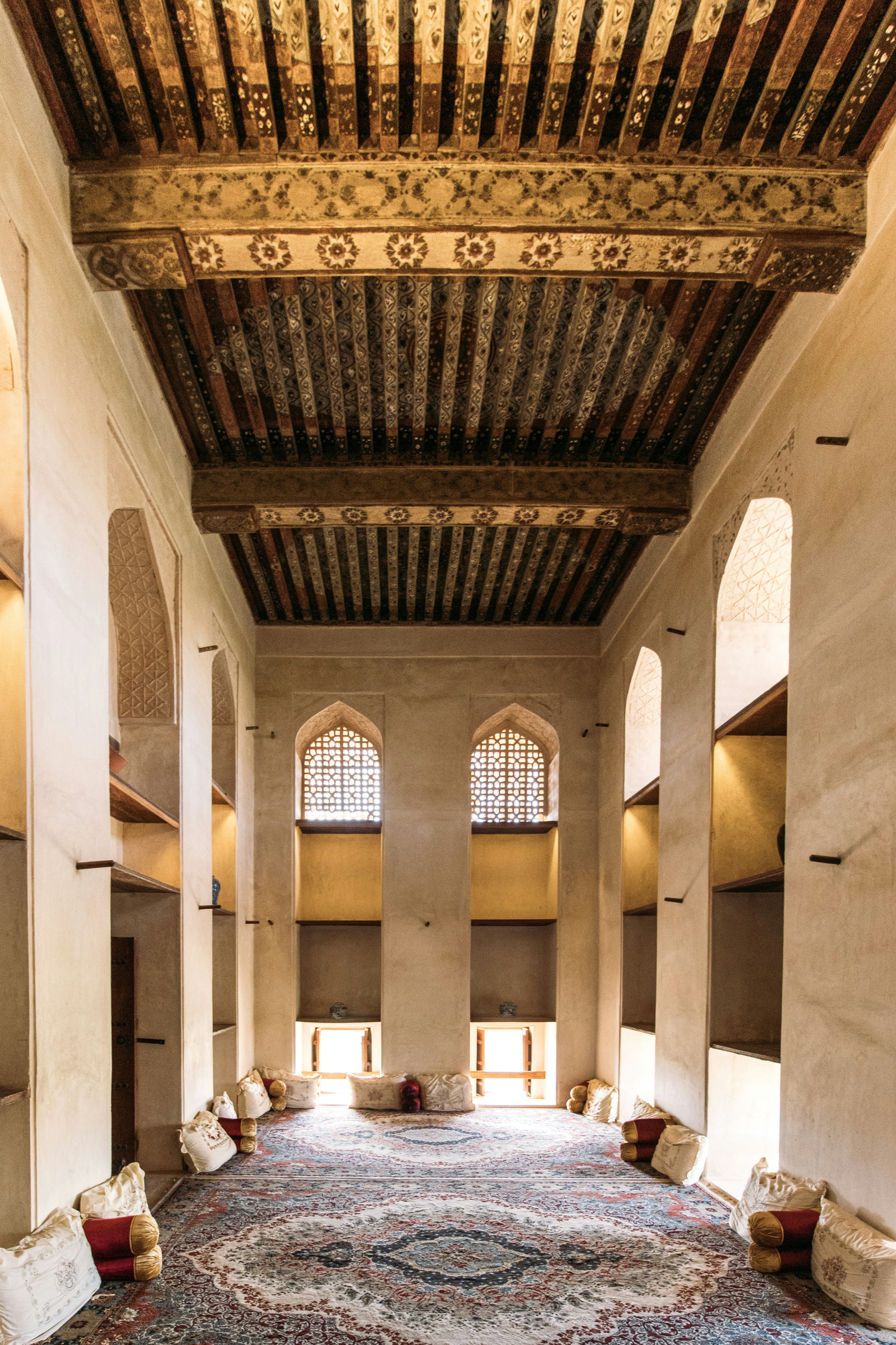 Sunlit Hallway: A Vaulted Oasis of Persian Carpets and Arched Windows