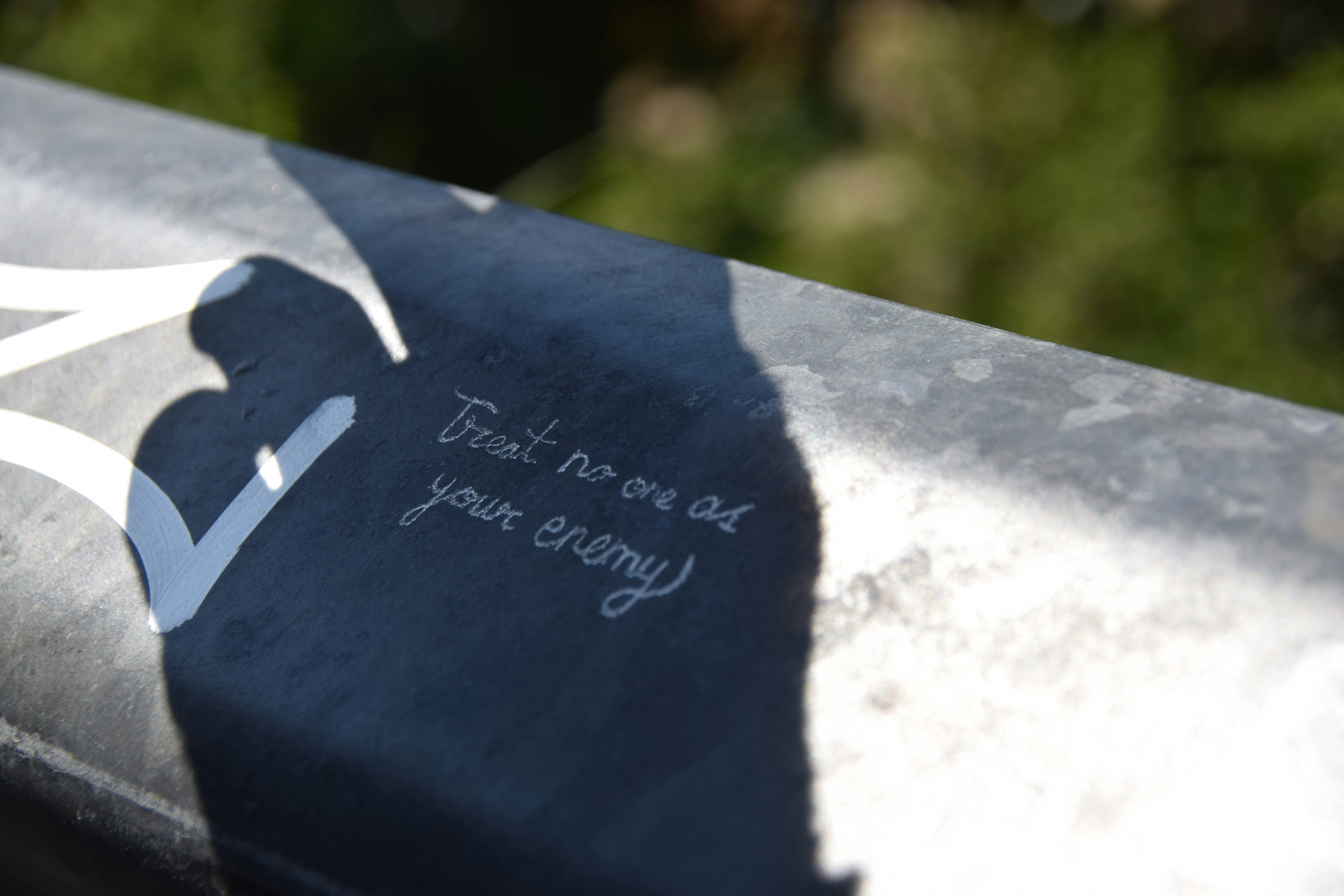 Shadowed Graffiti on Aged Metal: Message Beneath the Surface