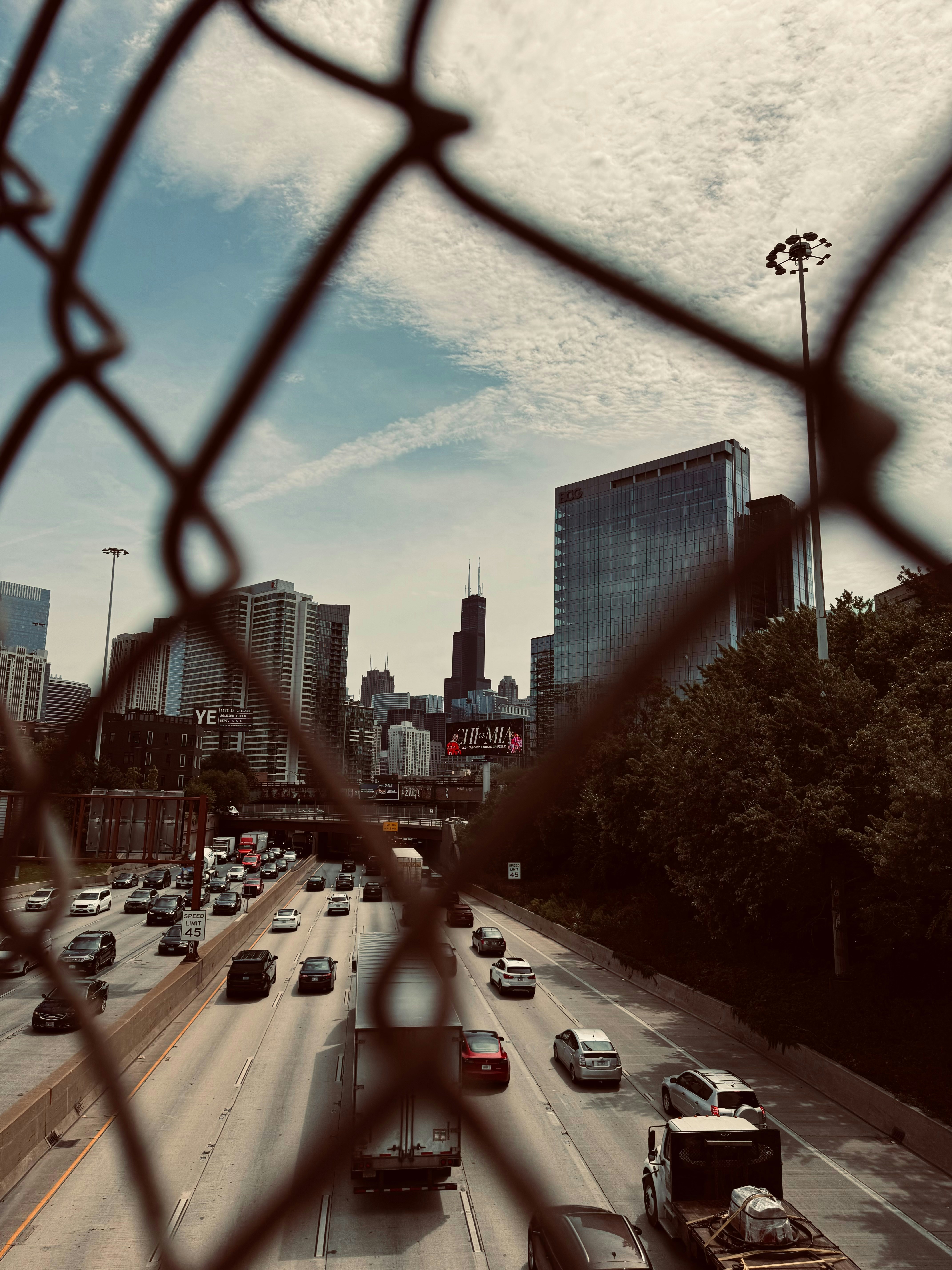City through a chain-link veil at rush hour